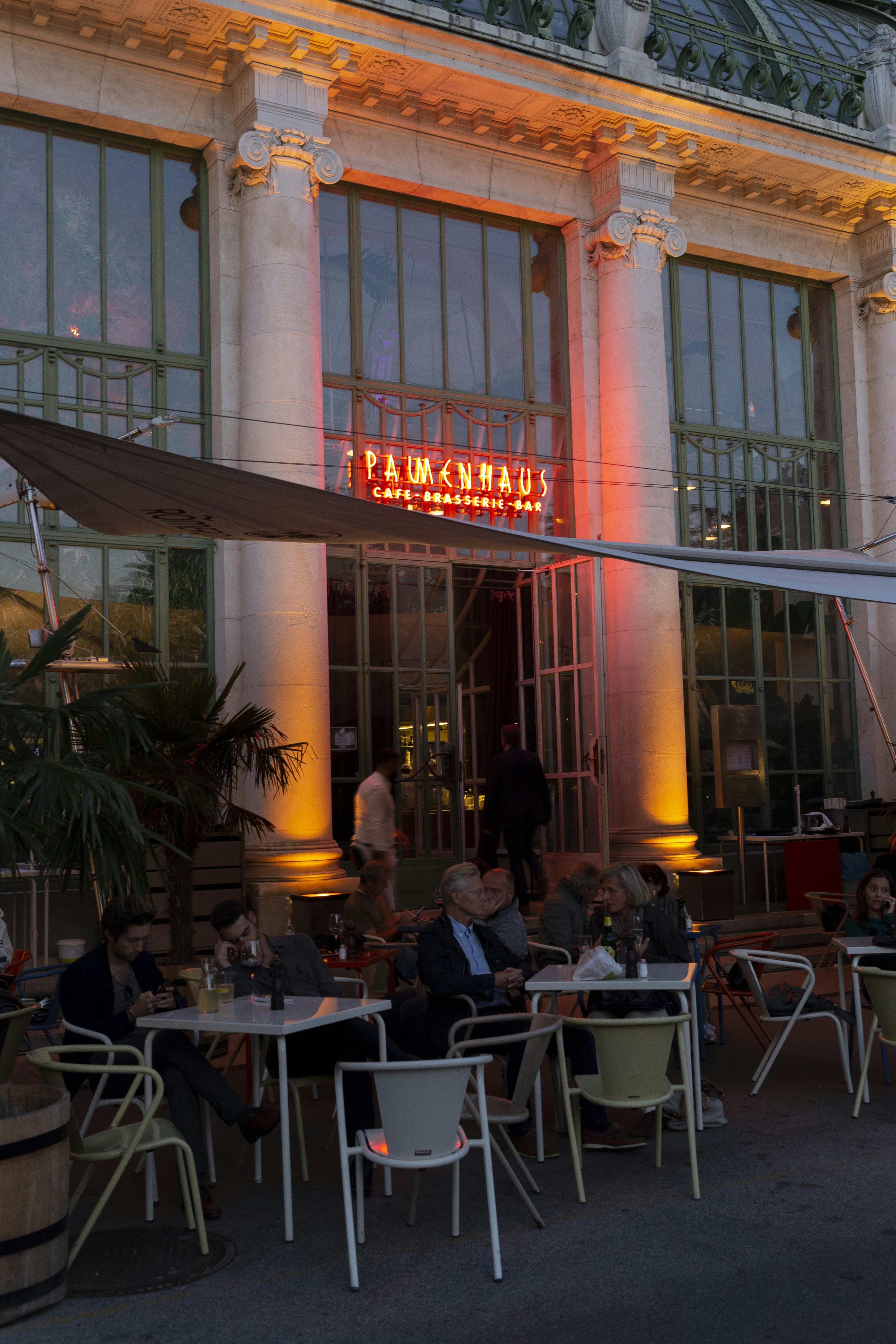 Neon Palmenhaus at Dusk: Warm Light Illuminates an Outdoor Café