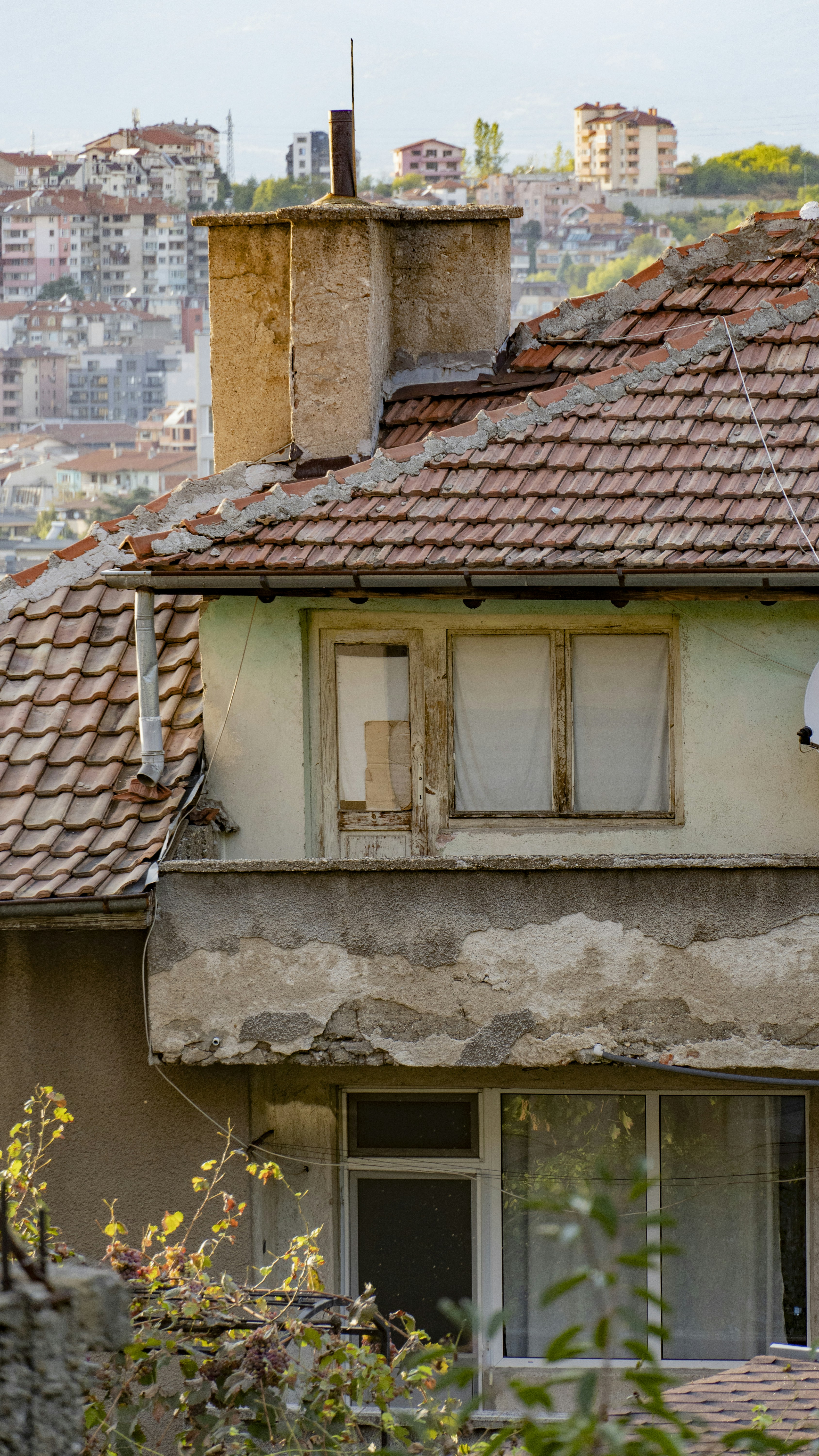 Rooftop Patina: Cracked Facade Framing a Distant City Horizon