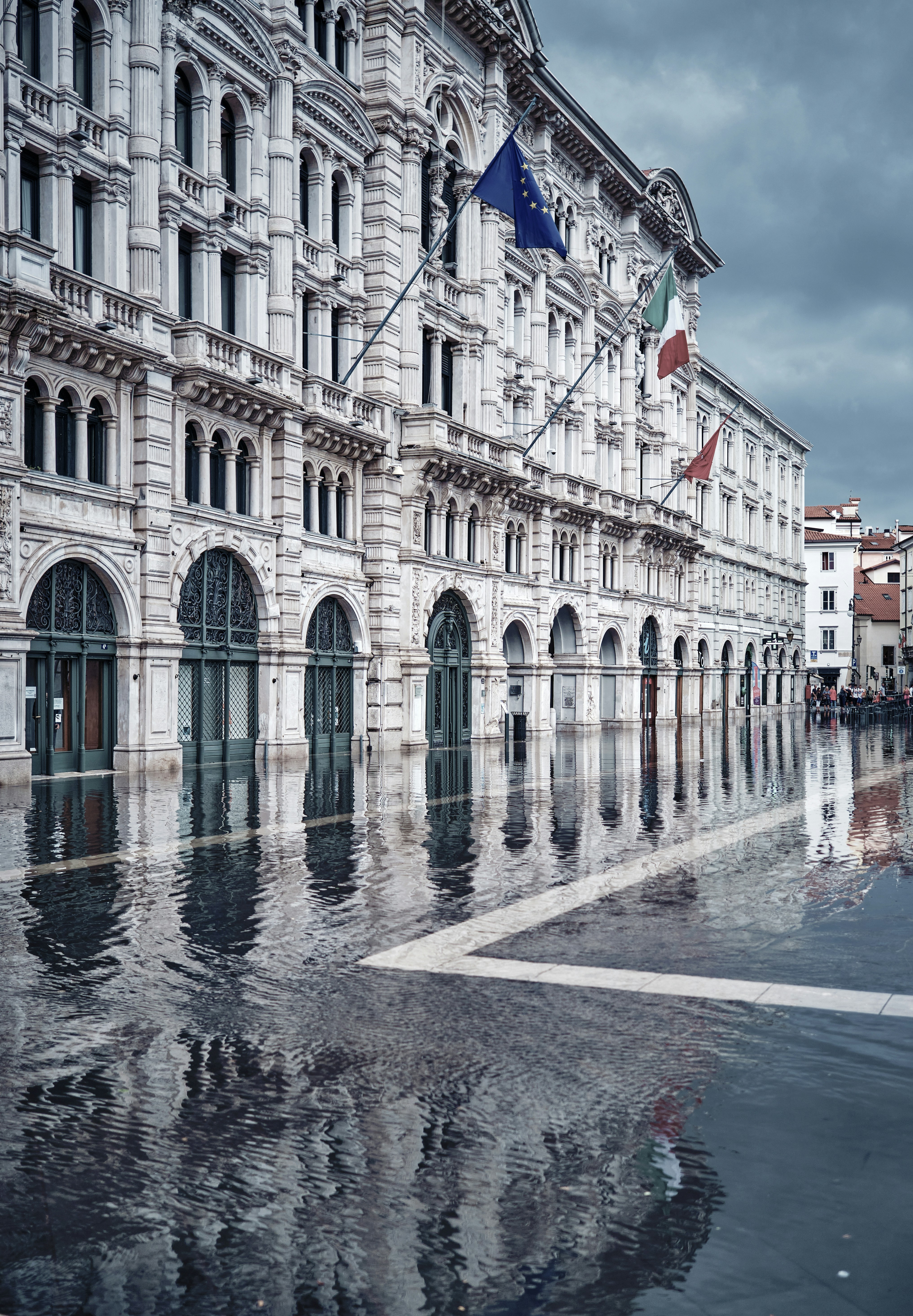 Arched Facade in Rain: Reflected Grandeur Across a Waterlogged Piazza