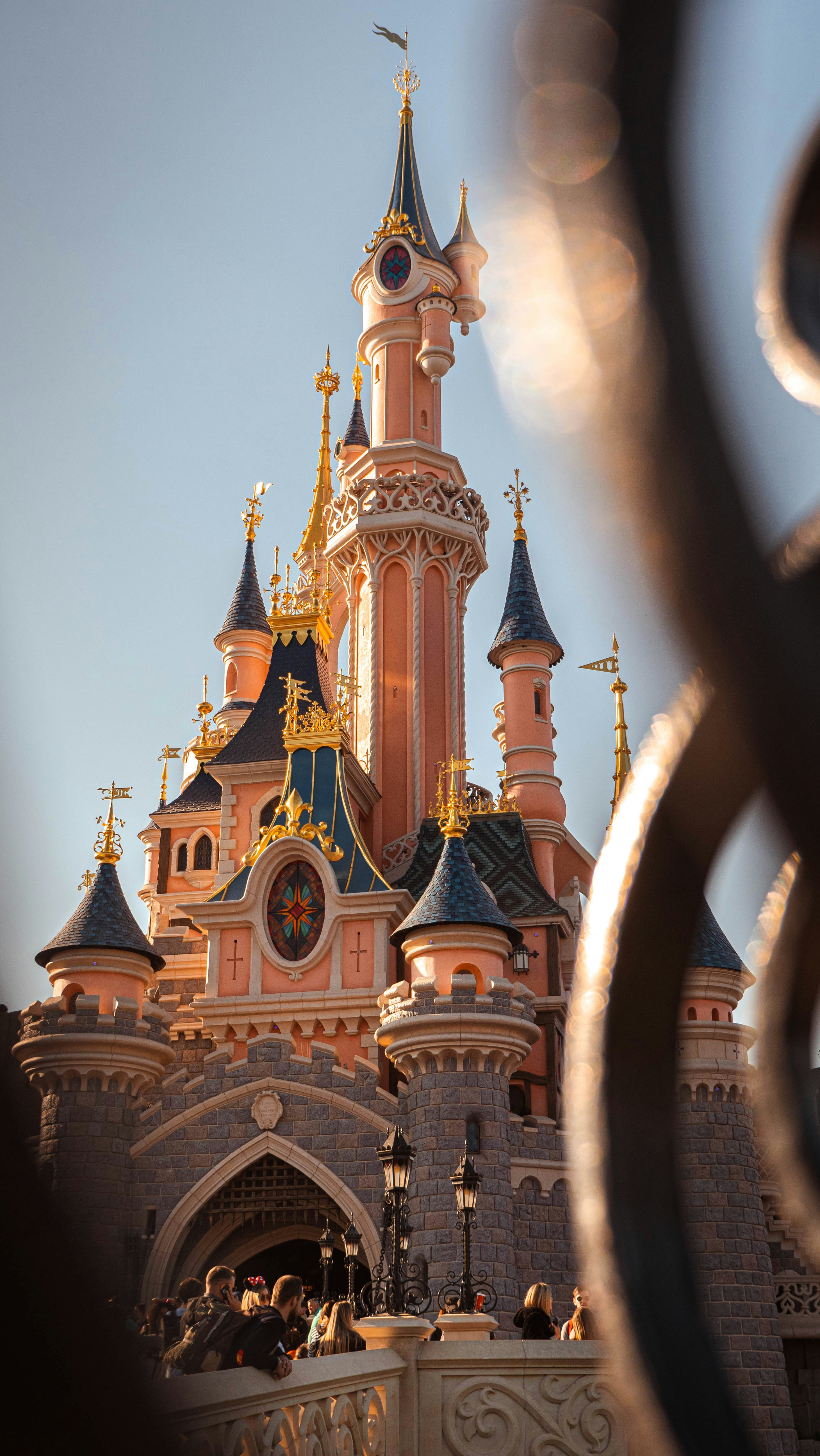 Fairy tale castle adorned with vibrant colors and intricate details, framed by an elegant wrought iron gate. 