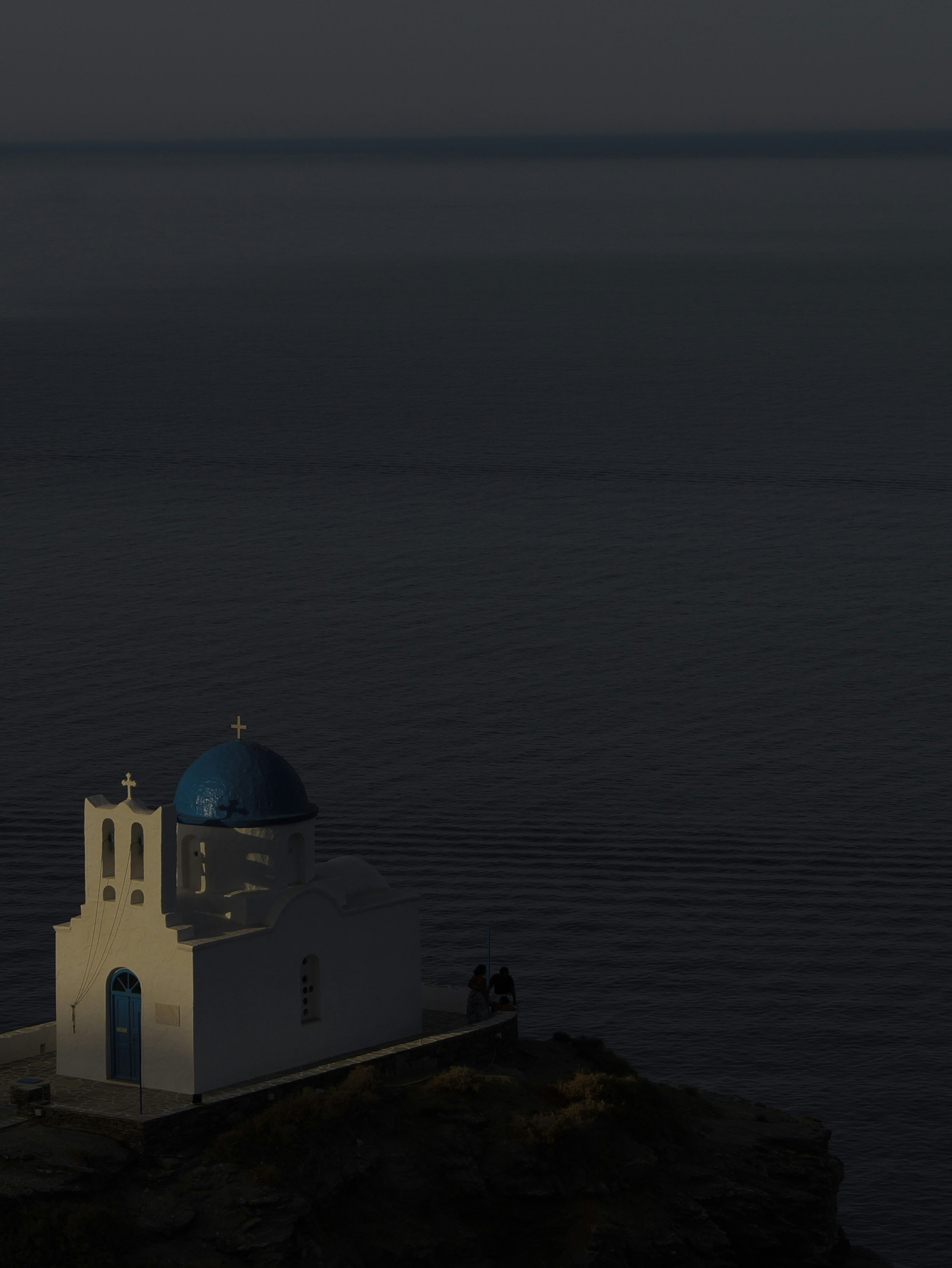 White chapel on a cliff under a dark sea horizon