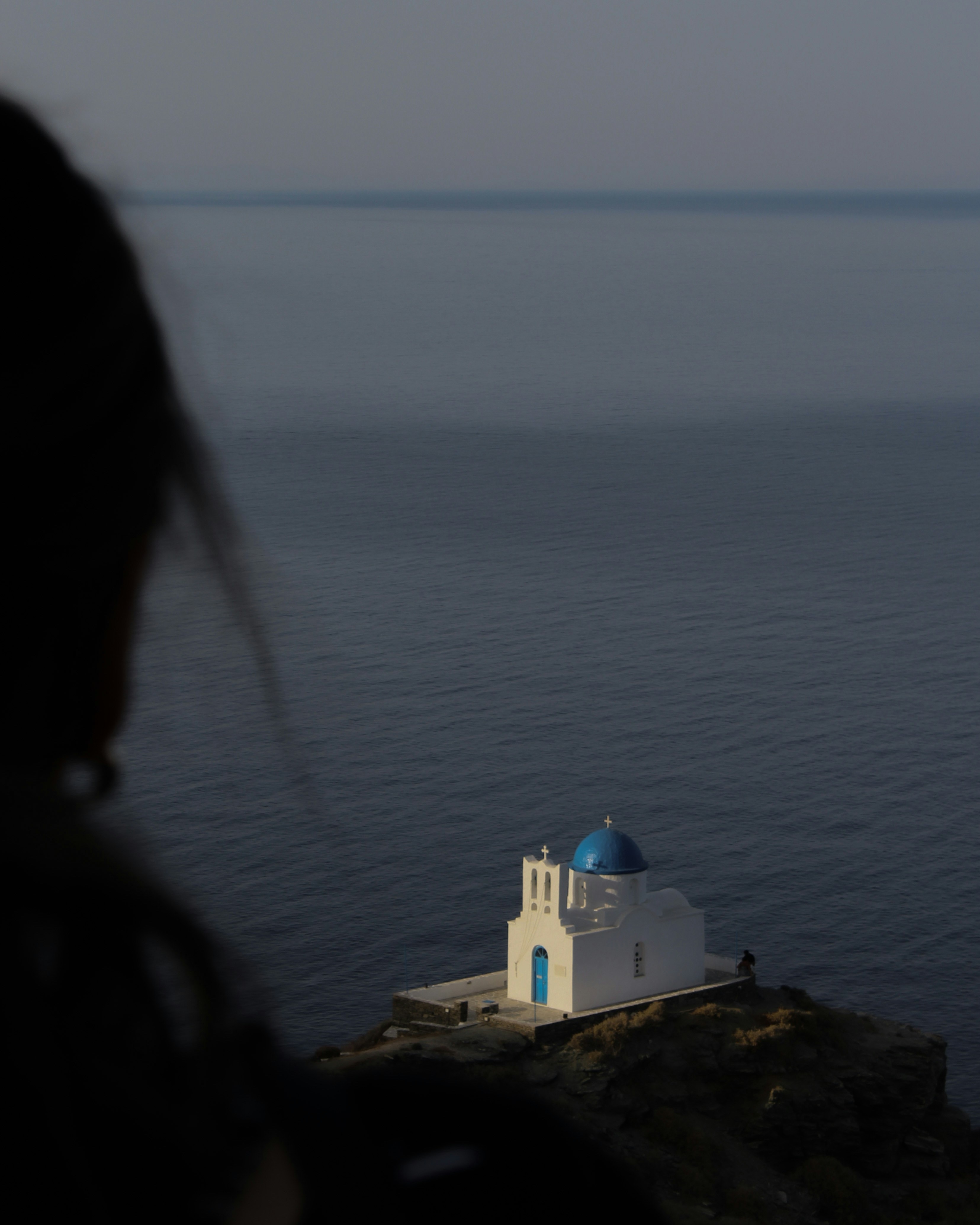 Blue-Domed Chapel at the Cliff's Edge, Framed by Foreground Shadow