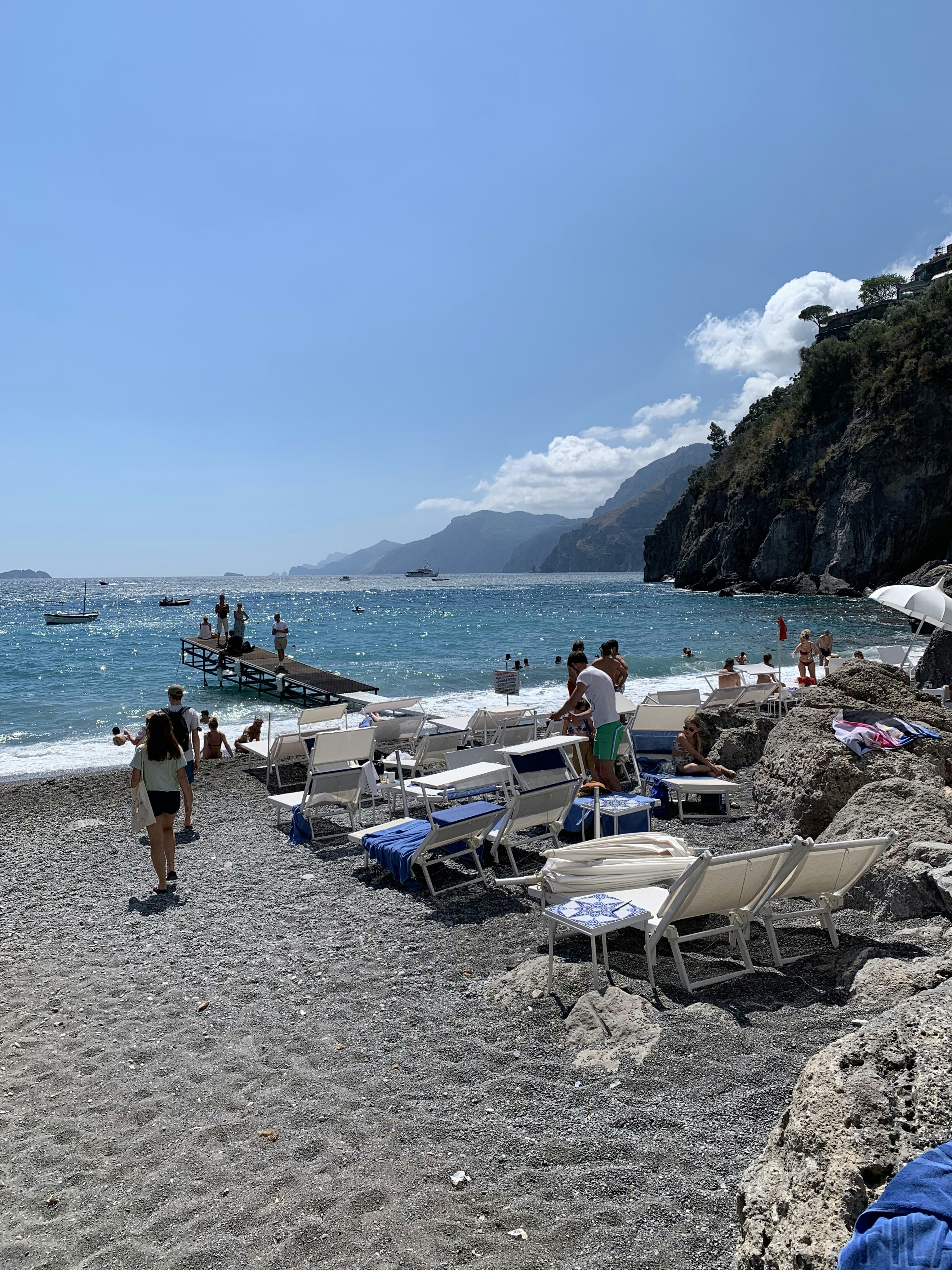 Cobalt Seafront: White Loungers Line a Cliffside Pebble Beach