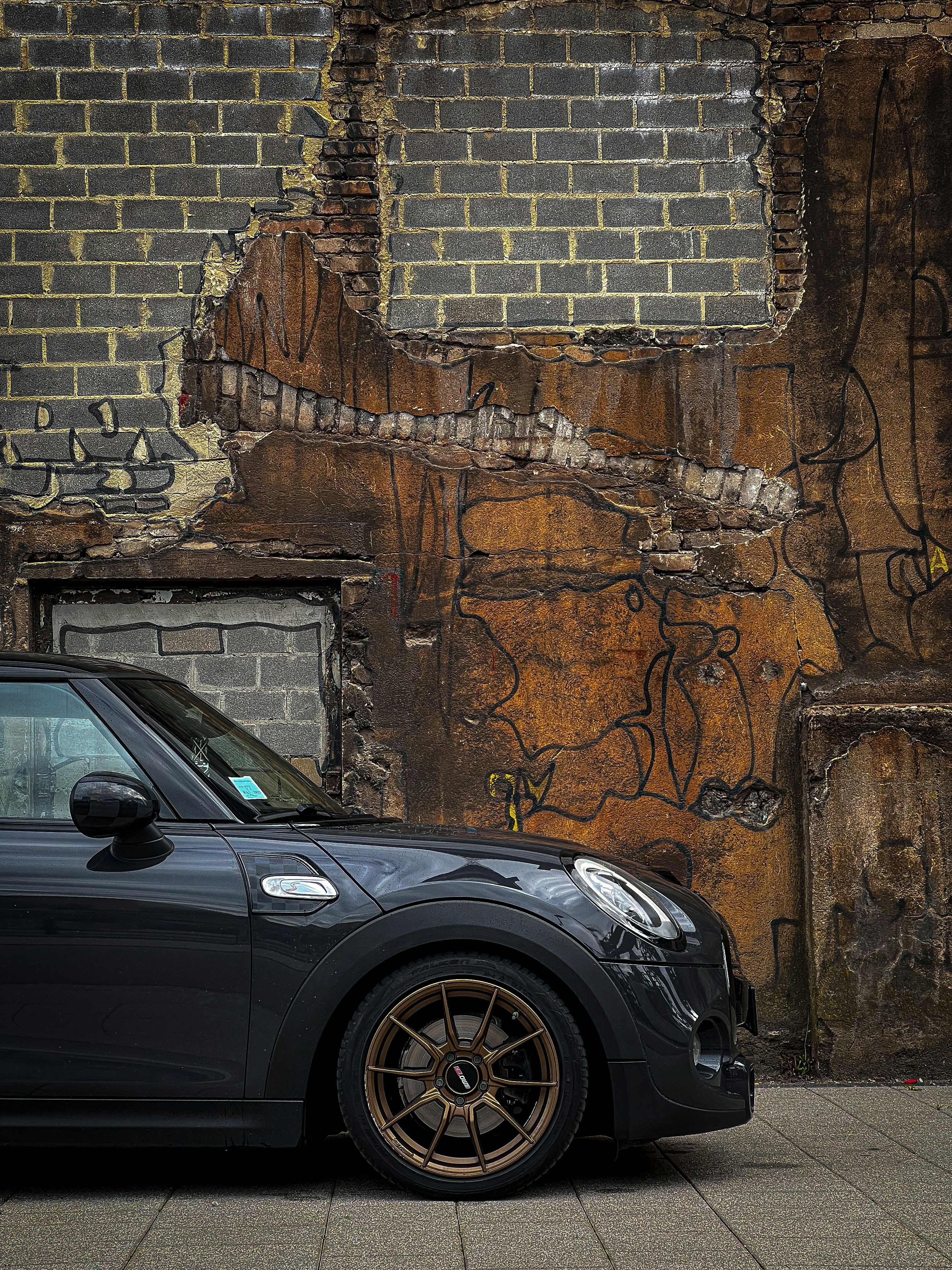 Bronze Wheels at the Edge of a Crumbling Brick Mural