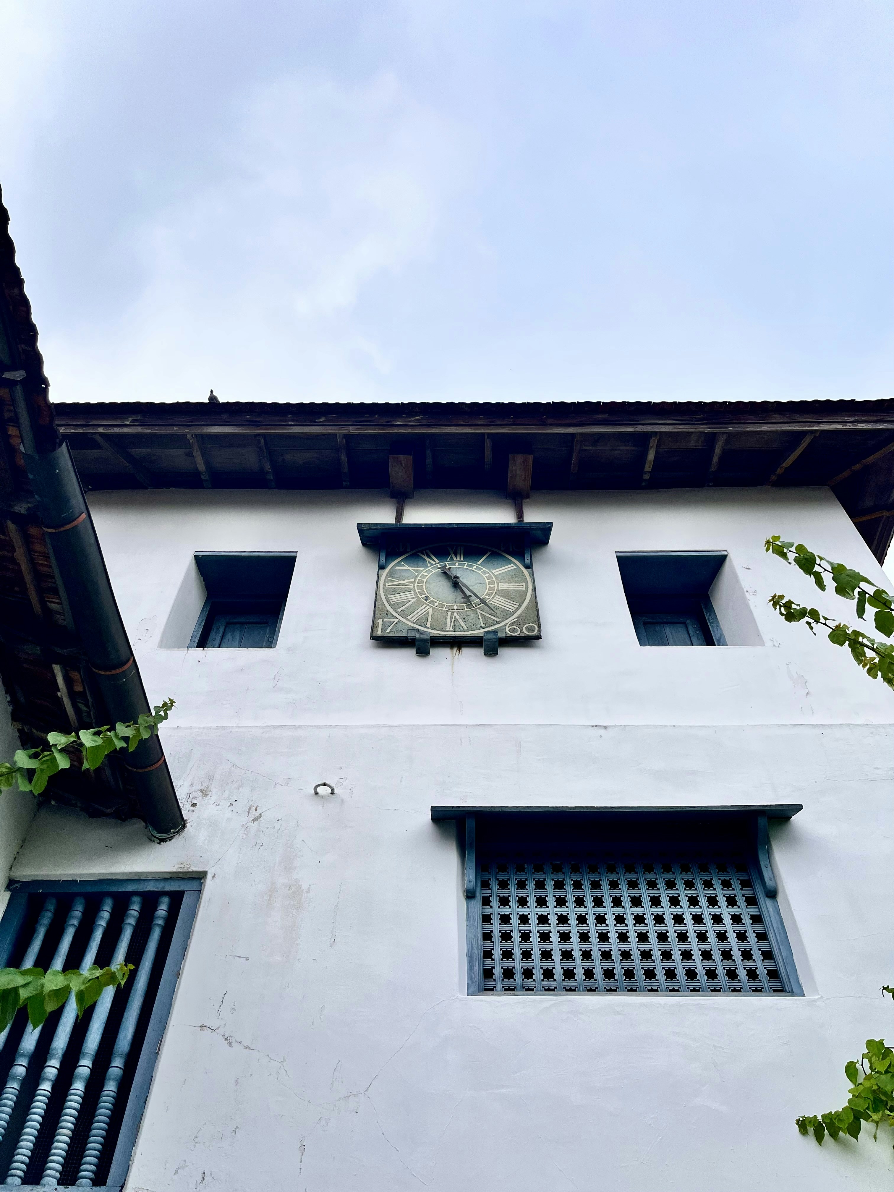 The Timekeeper Above the Lattice: A Quiet Facade Under a Clear Sky