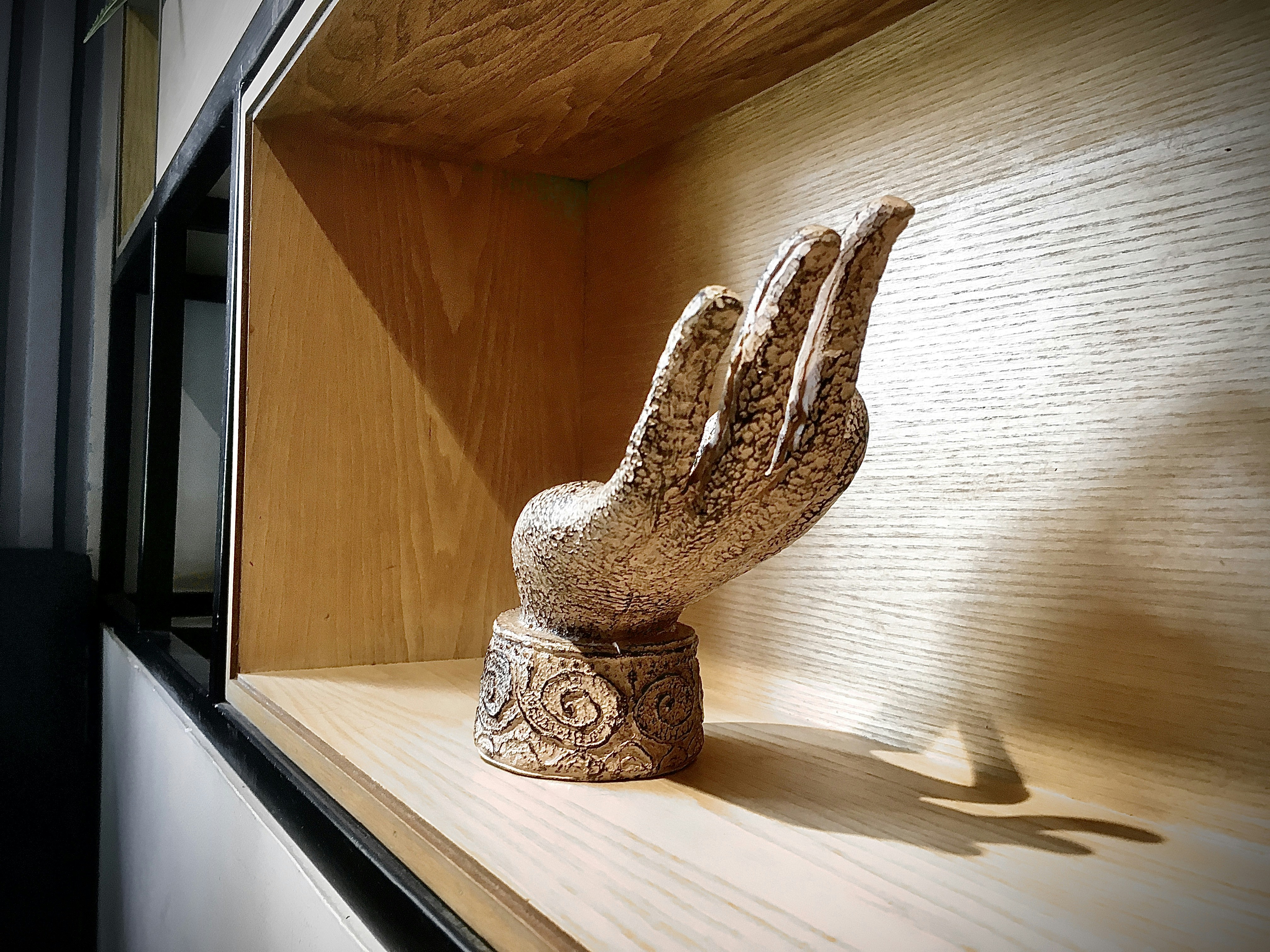 Sculpted Hand on a Wooden Shelf: Shadowed Still Life