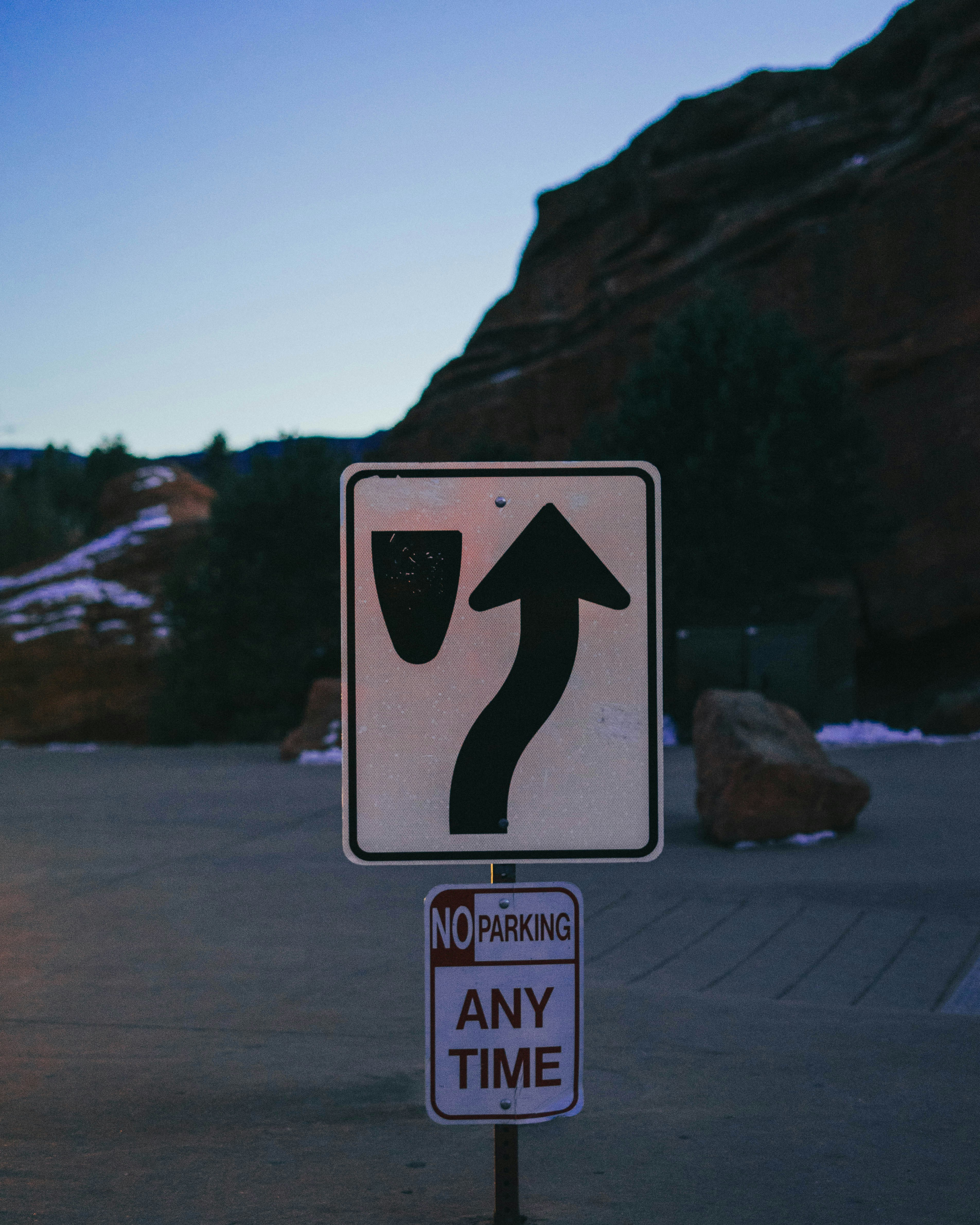 Twilight Turn: The Arrow Sign Stands Against a Rugged Cliff