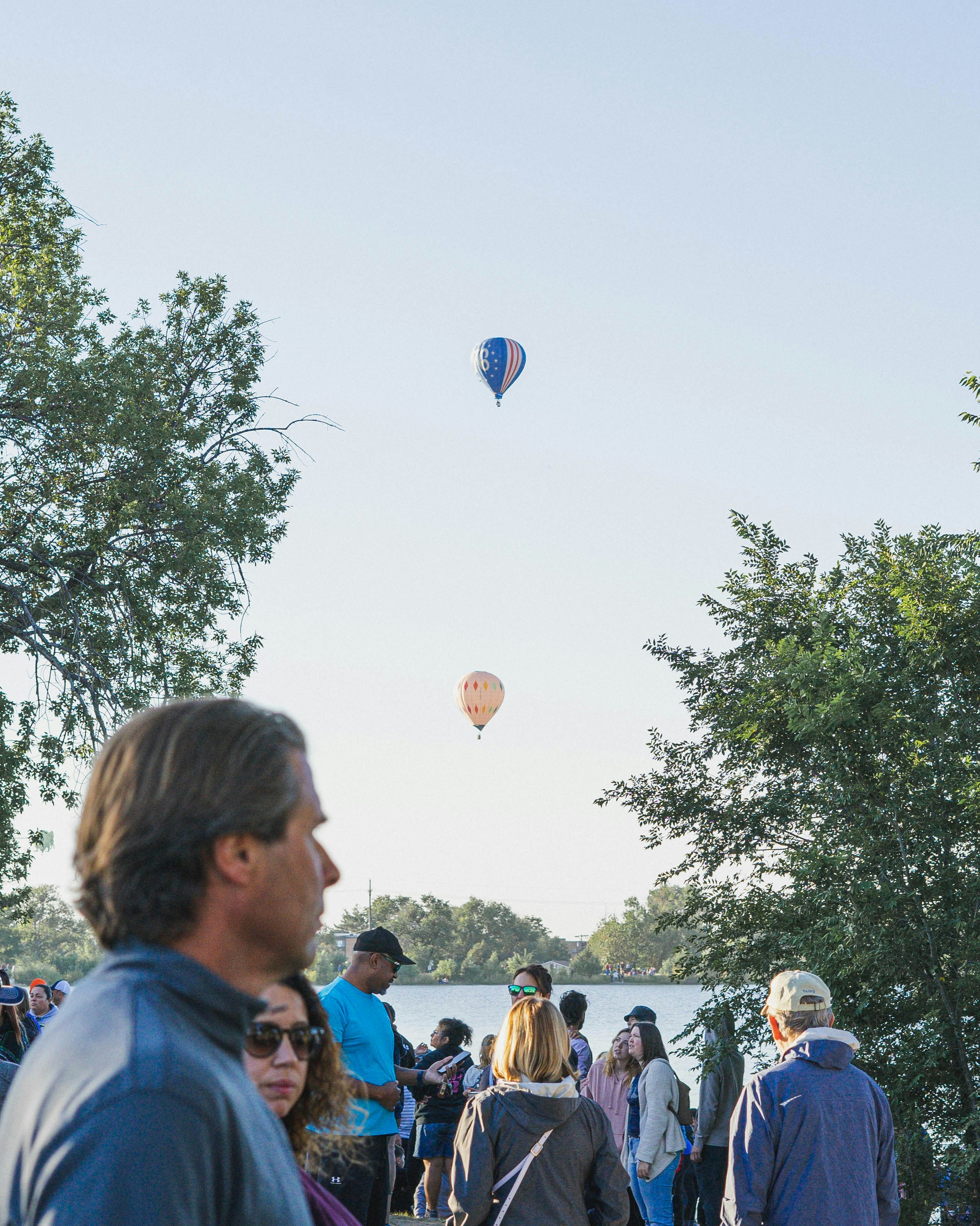 Twin Balloons Drift Over a Lively Lakeside Crowd
