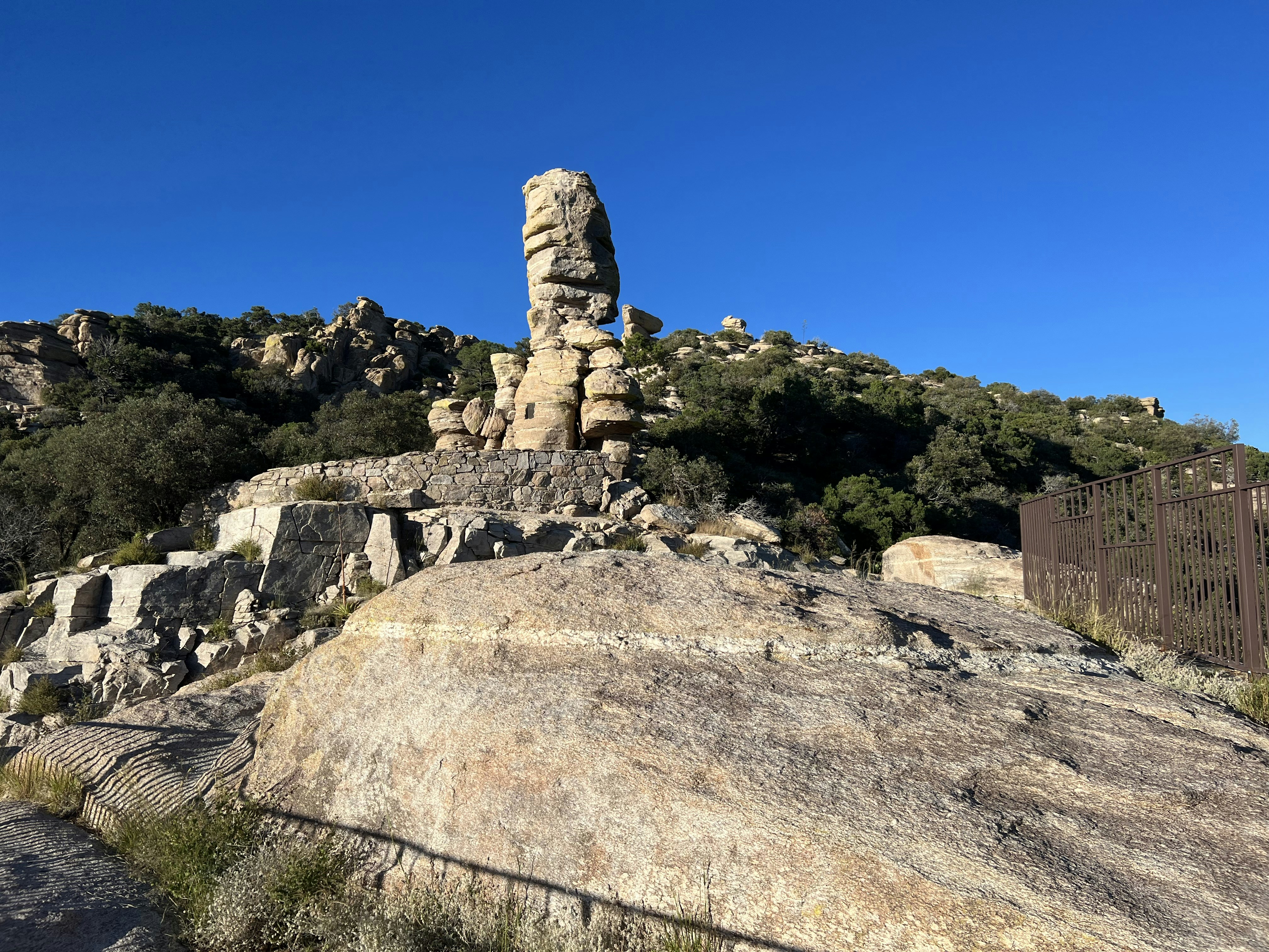 A large rock structure with a fence around it photo – Free Rock Image ...