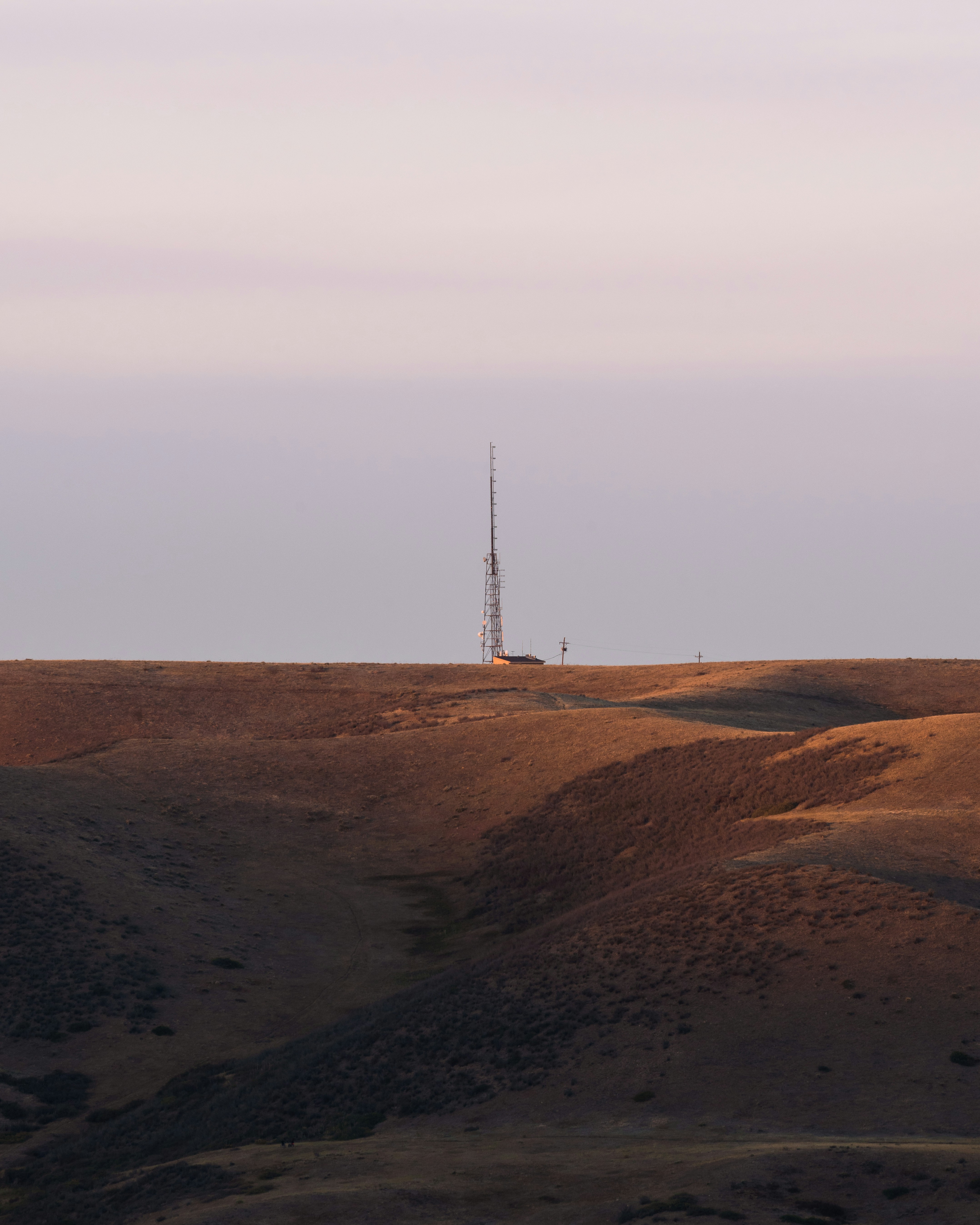 Horizon Signal: A Lone Antenna Standing on Dune-Like Hills at Twilight