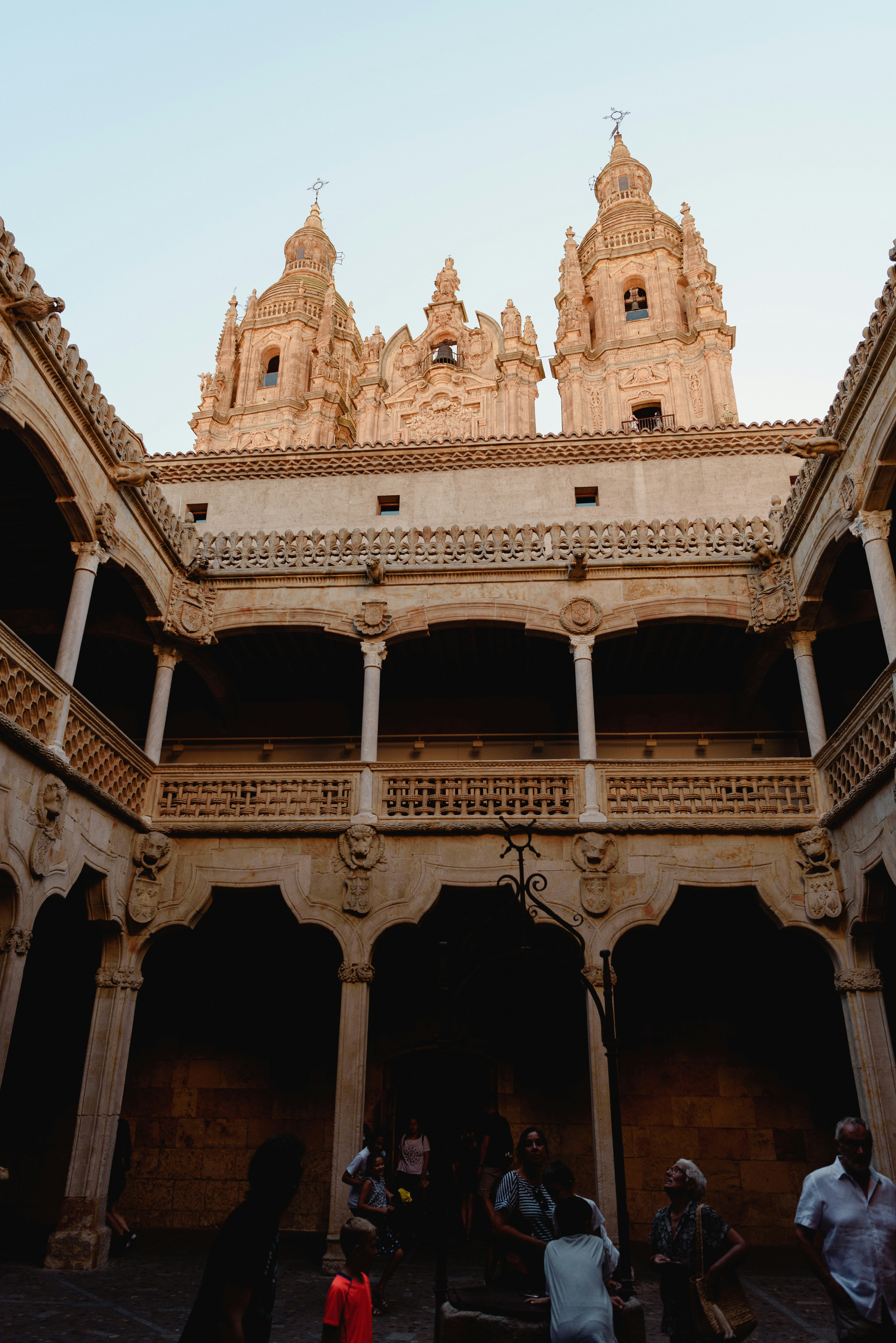 View of a church in Salamanca framed by the ornate arches of Casa de las Conchas courtyard.