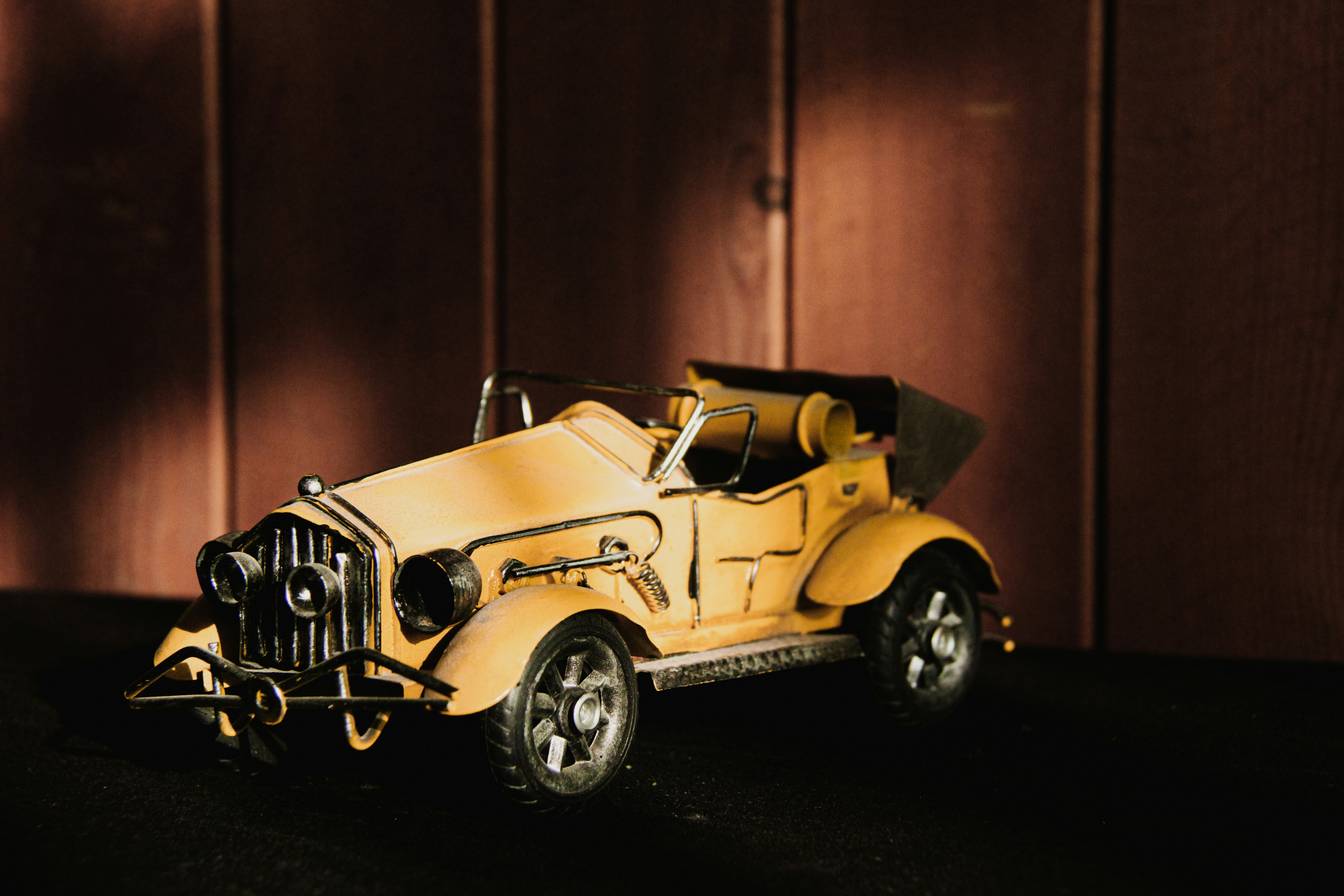 Spotlit Yellow Miniature Convertible Against a Wood-Warm Studio Backdrop