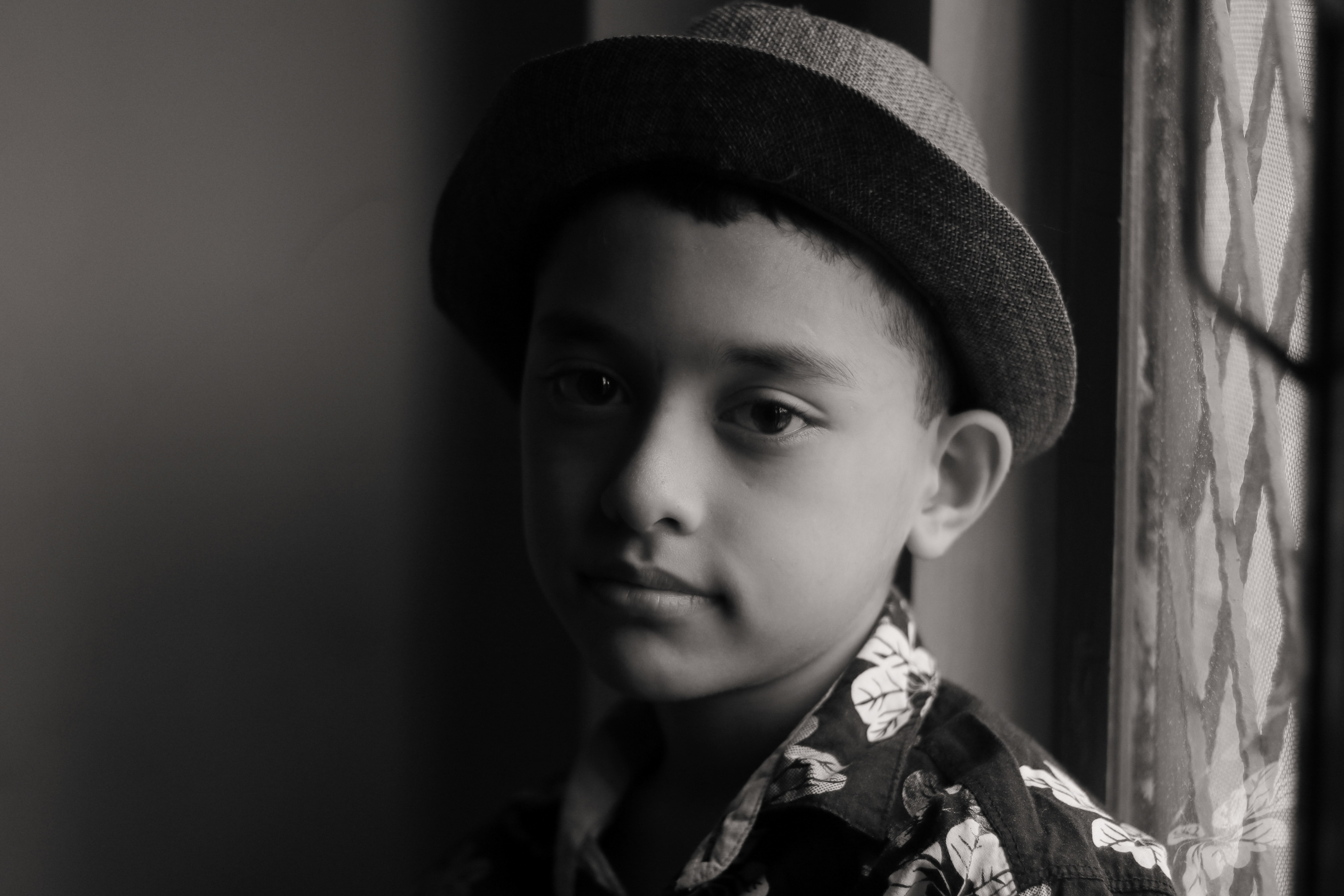Quiet Stillness: A Boy in a Fedora by the Window
