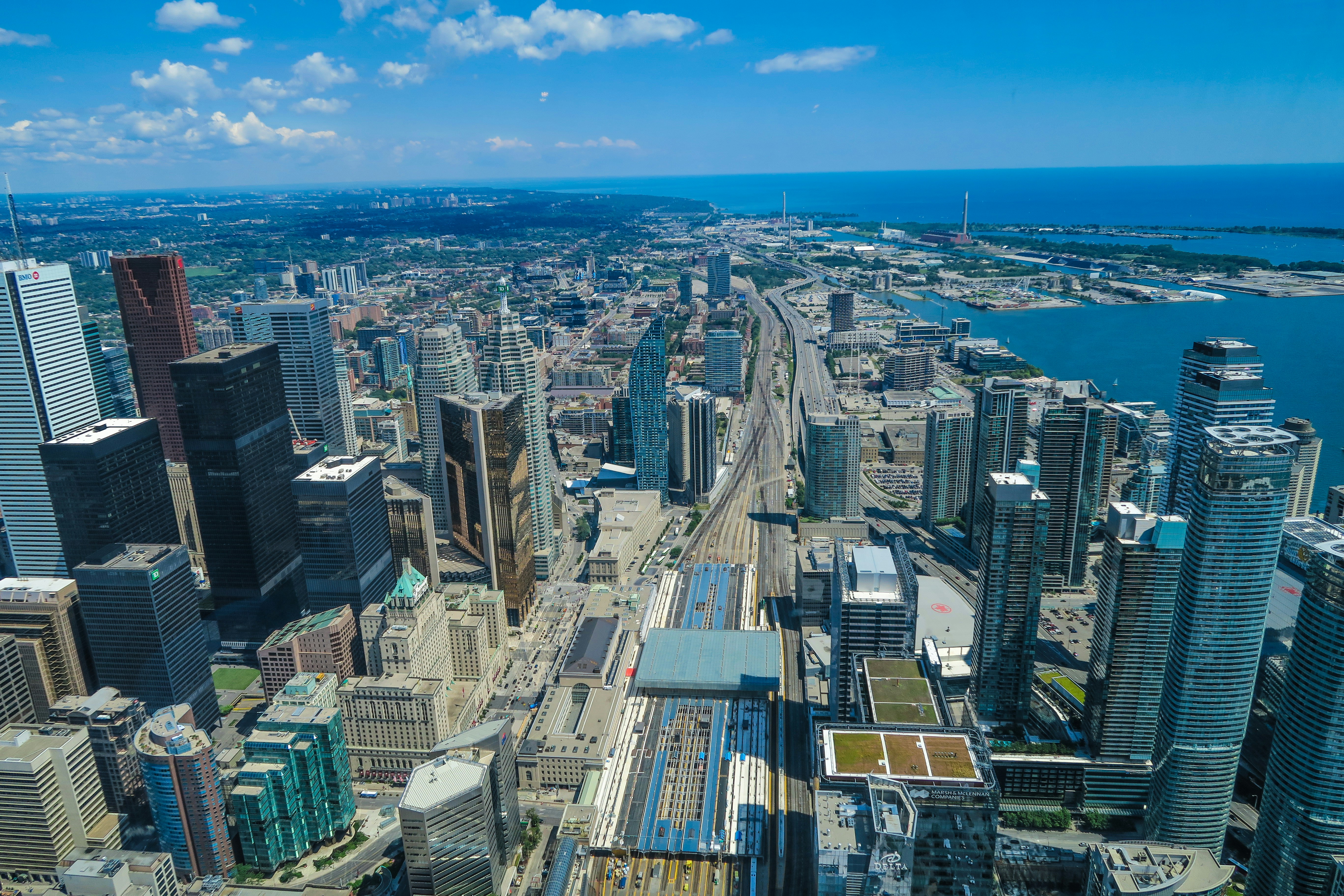 Aerial view showcasing a vibrant city skyline with towering skyscrapers and a winding railway, set against a clear blue sky and shimmering lake.