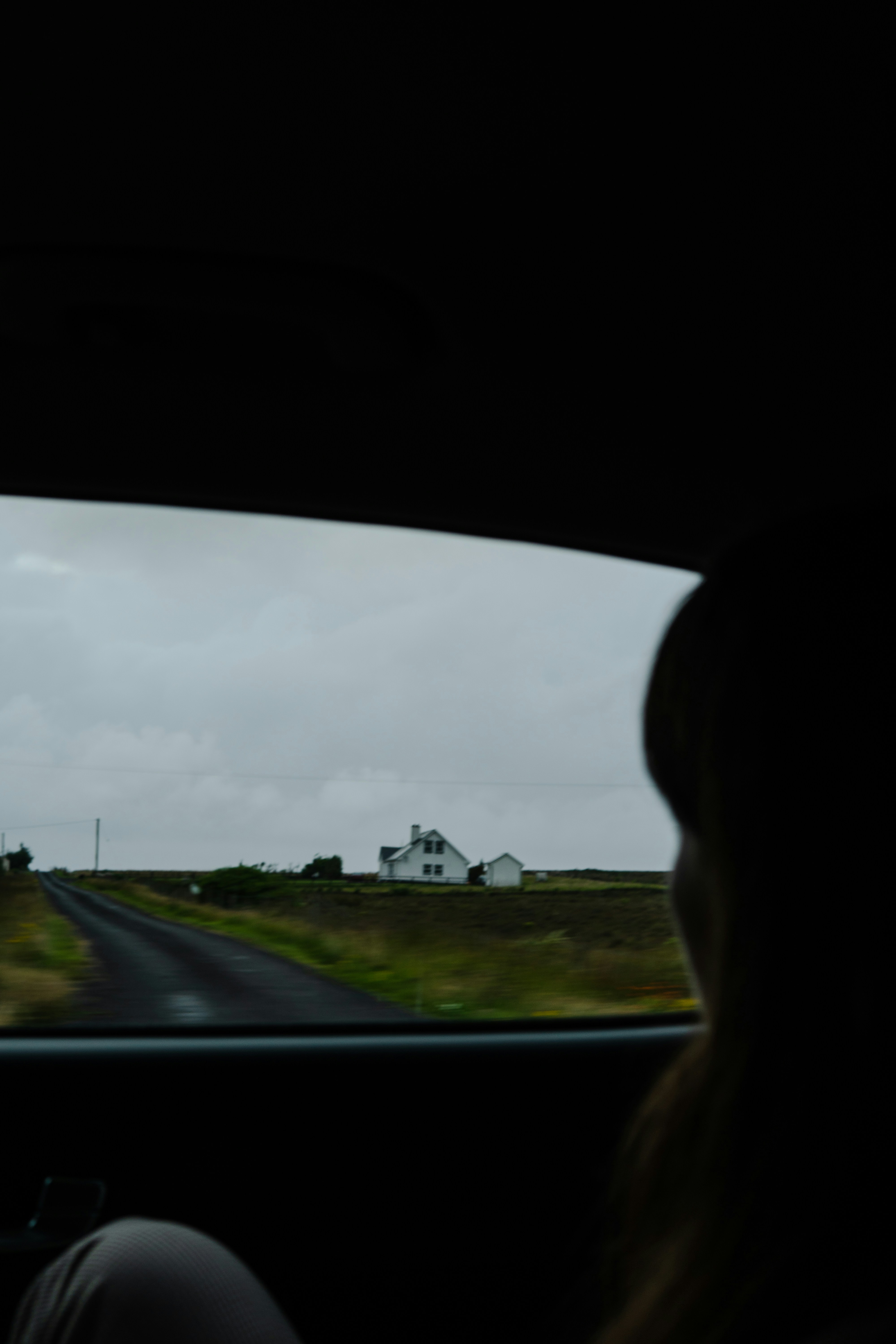 White Farmhouse on a Quiet Rural Road, Seen from a Car Window