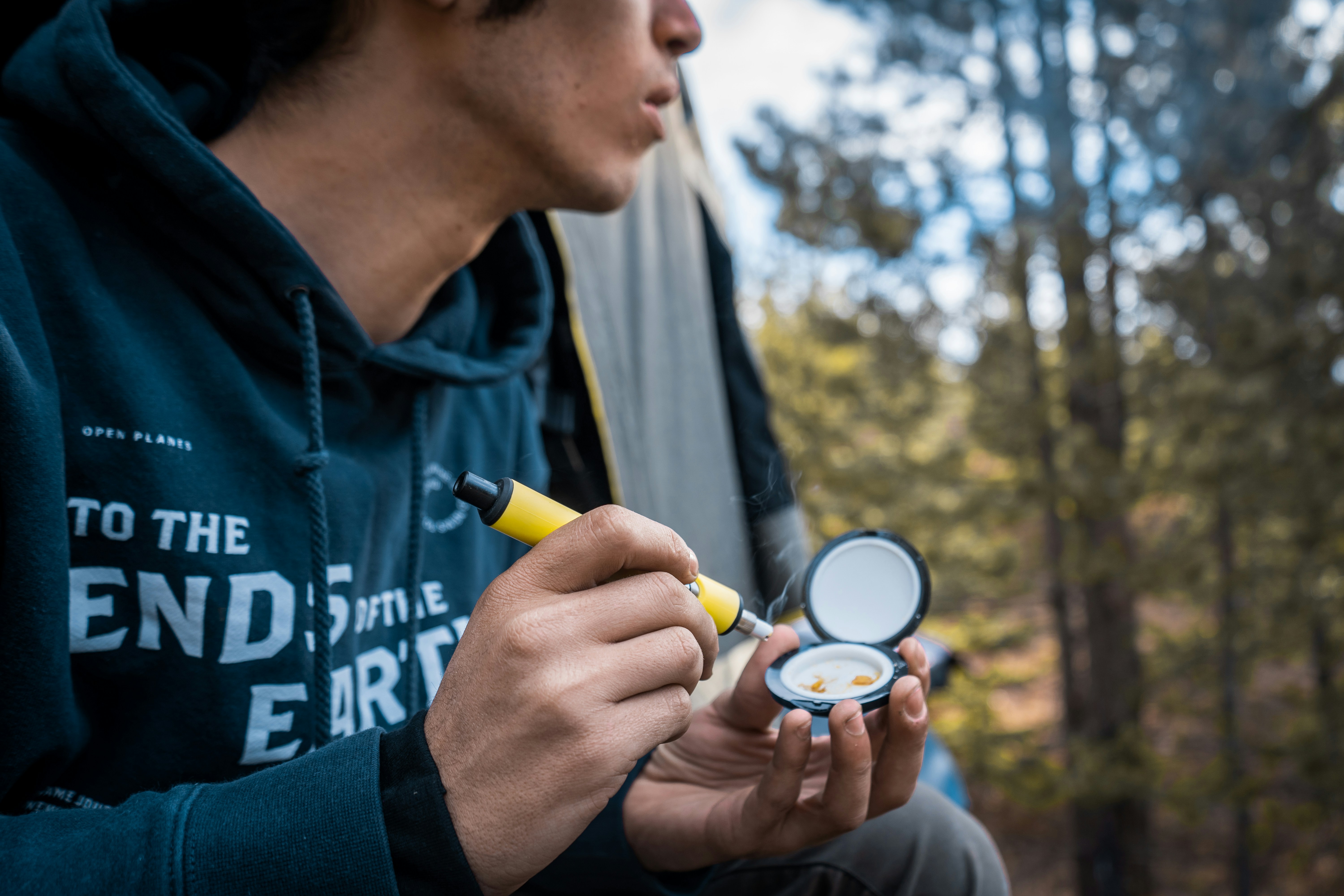 Person using a portable device while seated in a forest setting.