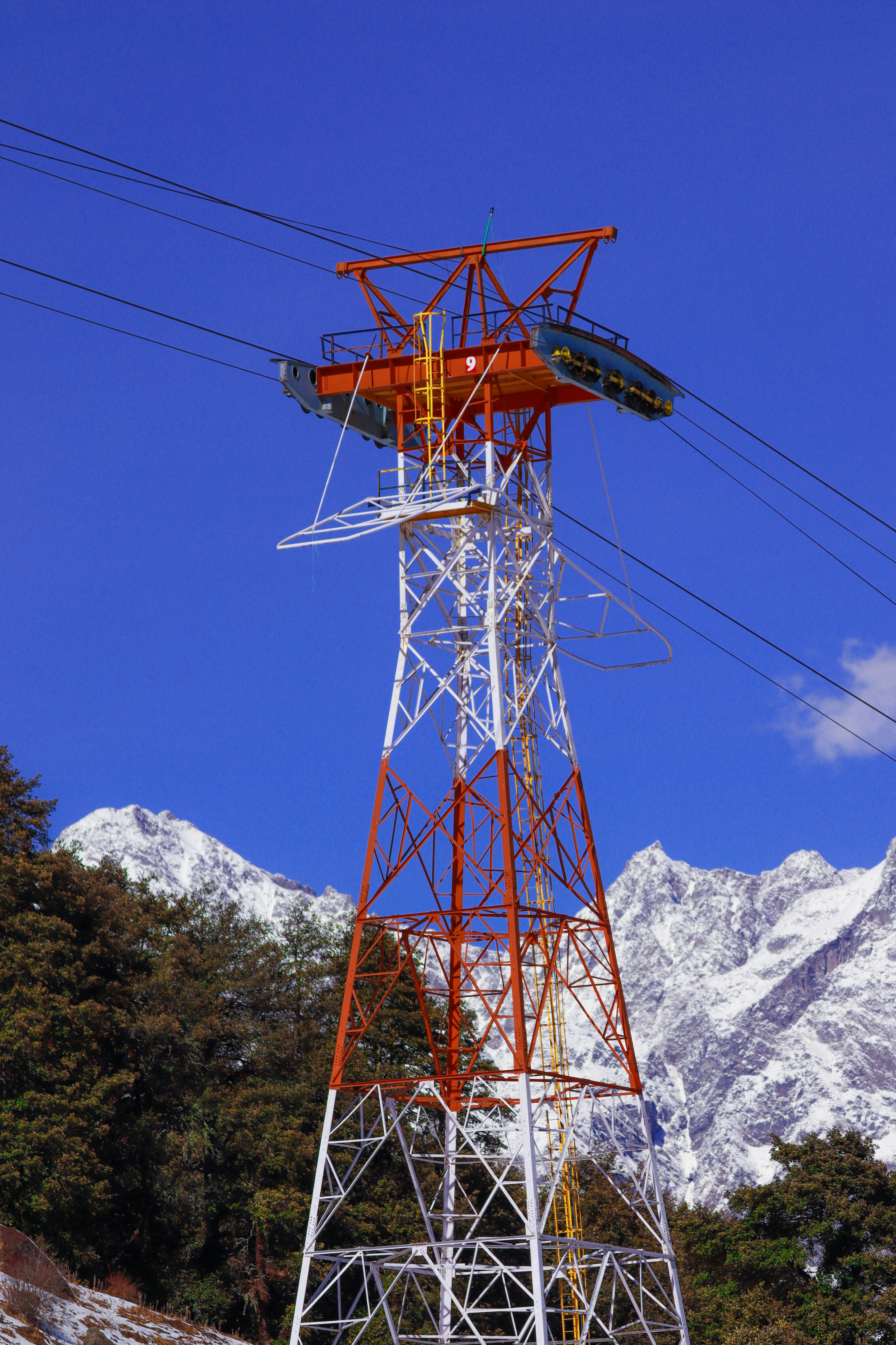 Alpine Lattice at Noon: A Red-Topped Ski Lift Tower Against Blue Peaks