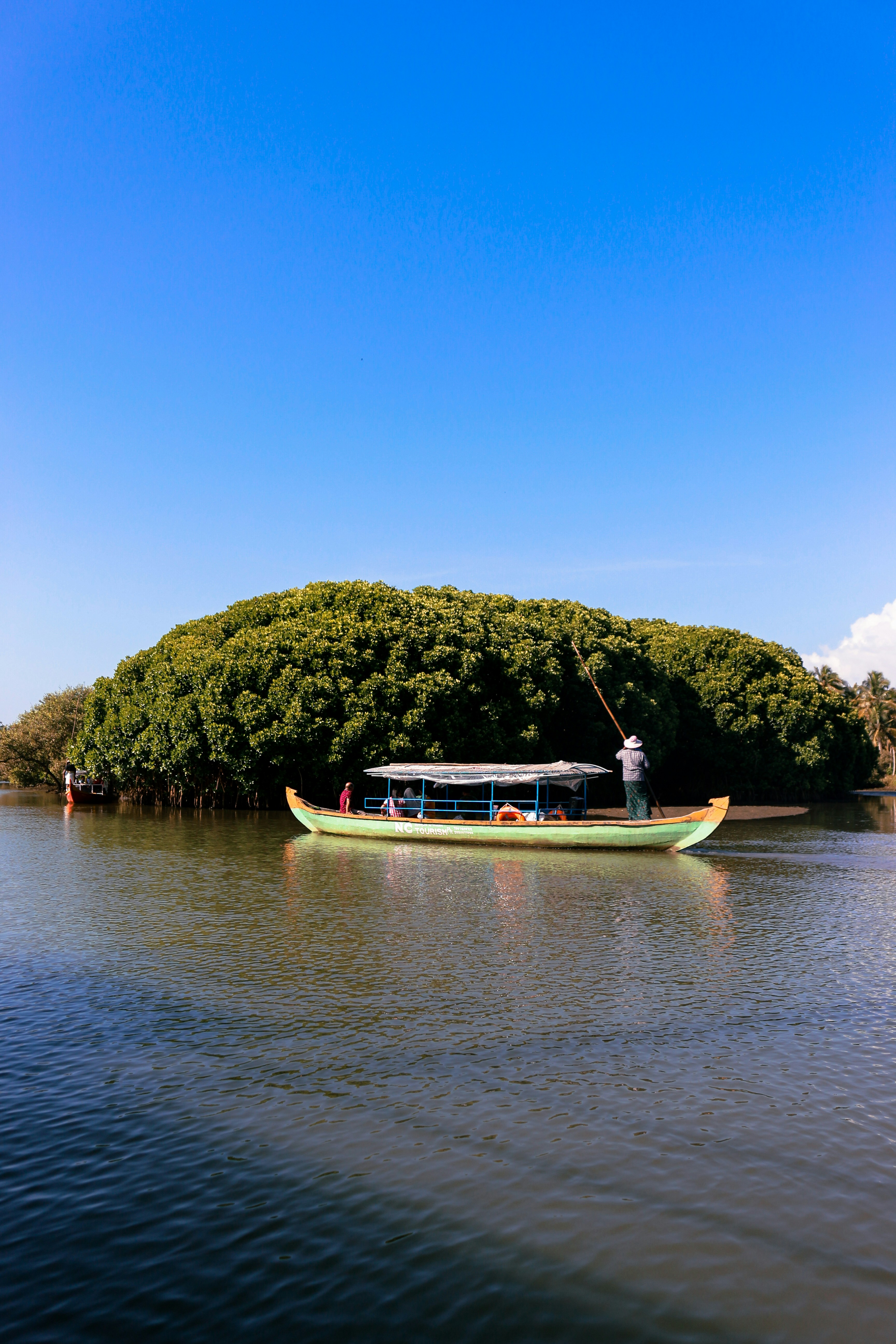 Green Boat, Quiet Crossing: Mangrove Gate Under a Pristine Sky
