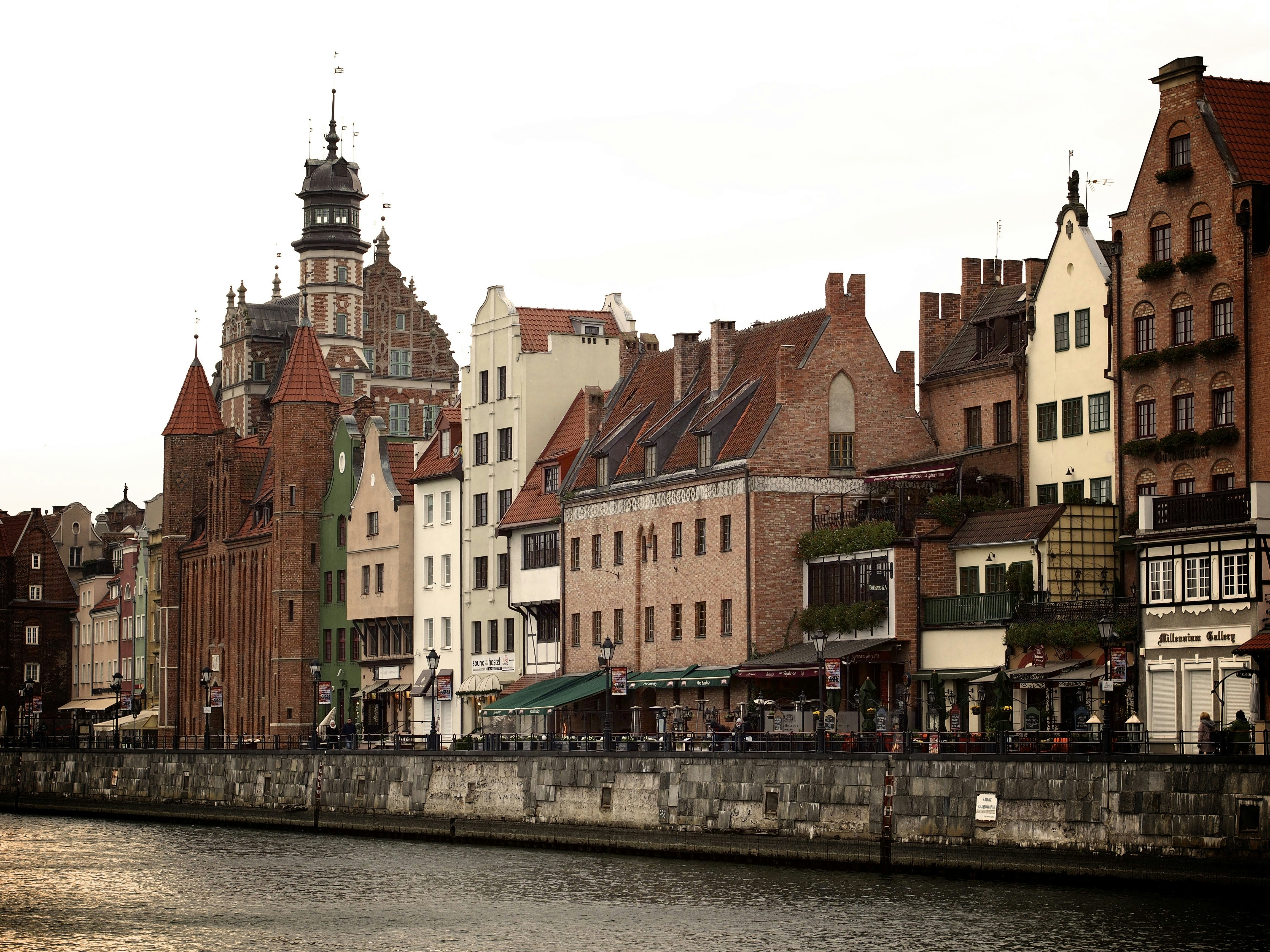 Historic buildings lining the waterfront of Gdańsk, showcasing a mix of architectural styles and vibrant colors.