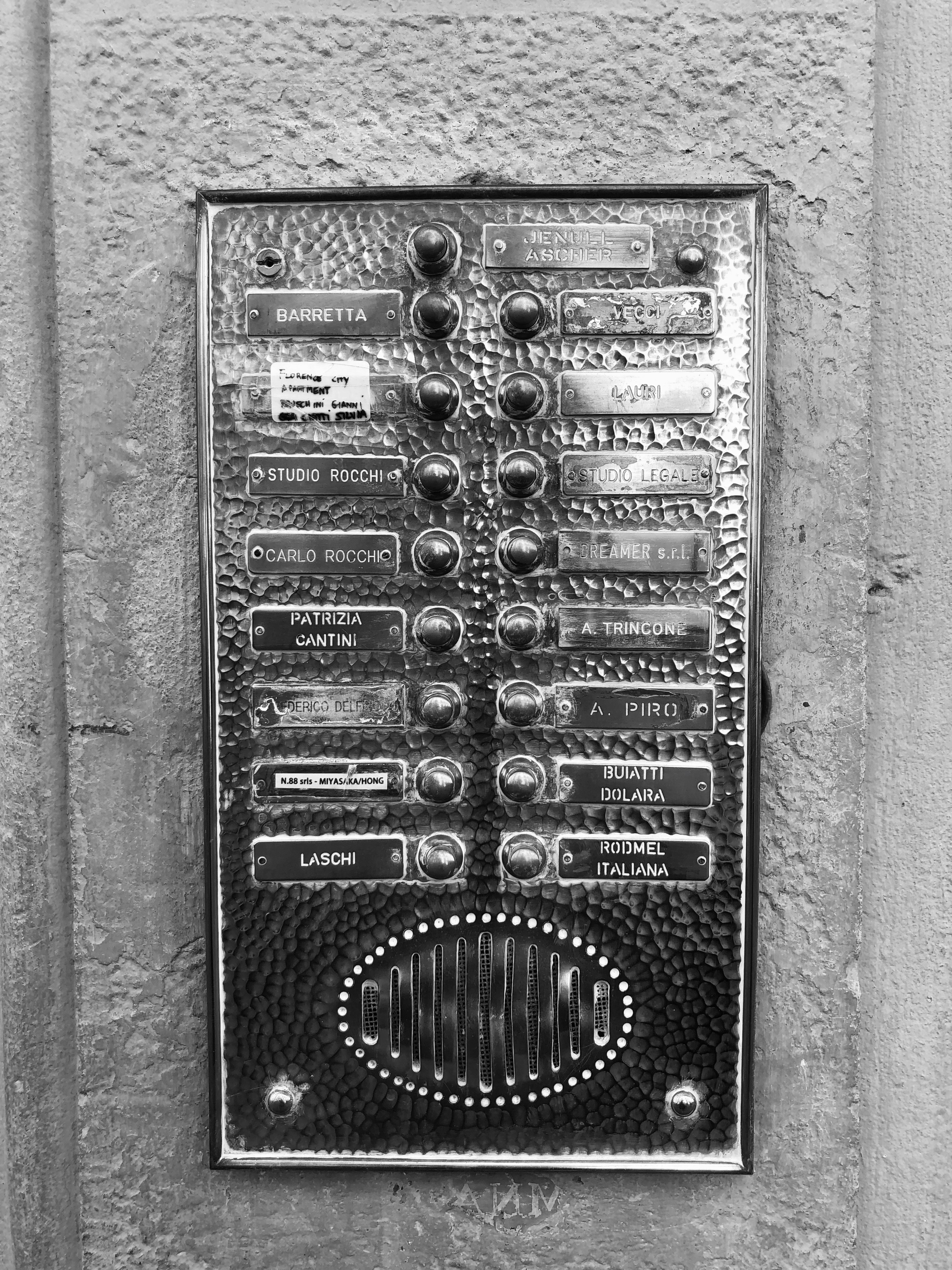 A vintage intercom panel featuring multiple nameplates and buttons, showcasing the blend of functionality and design in urban architecture.