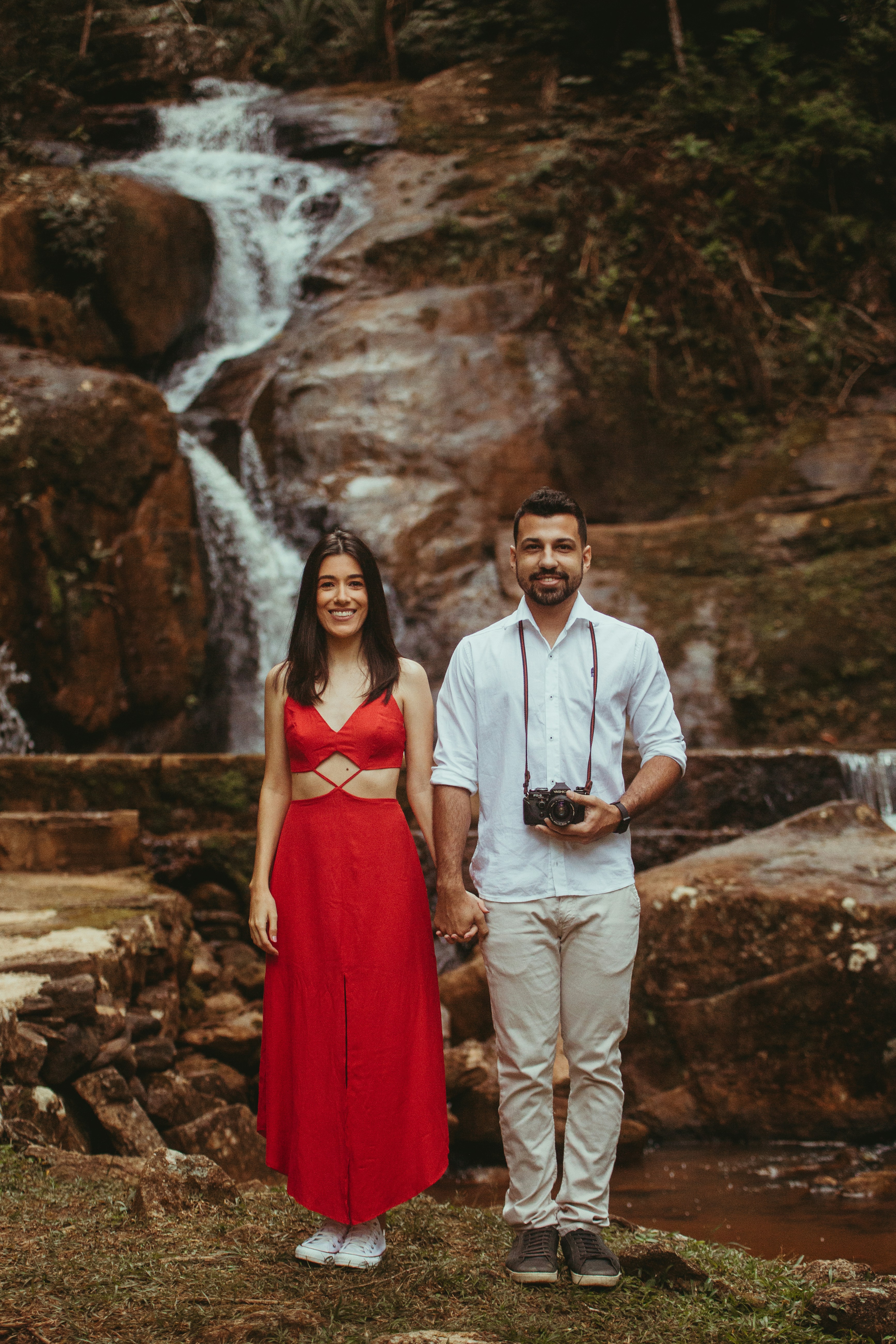 A man and woman posing for a picture in front of a waterfall photo ...