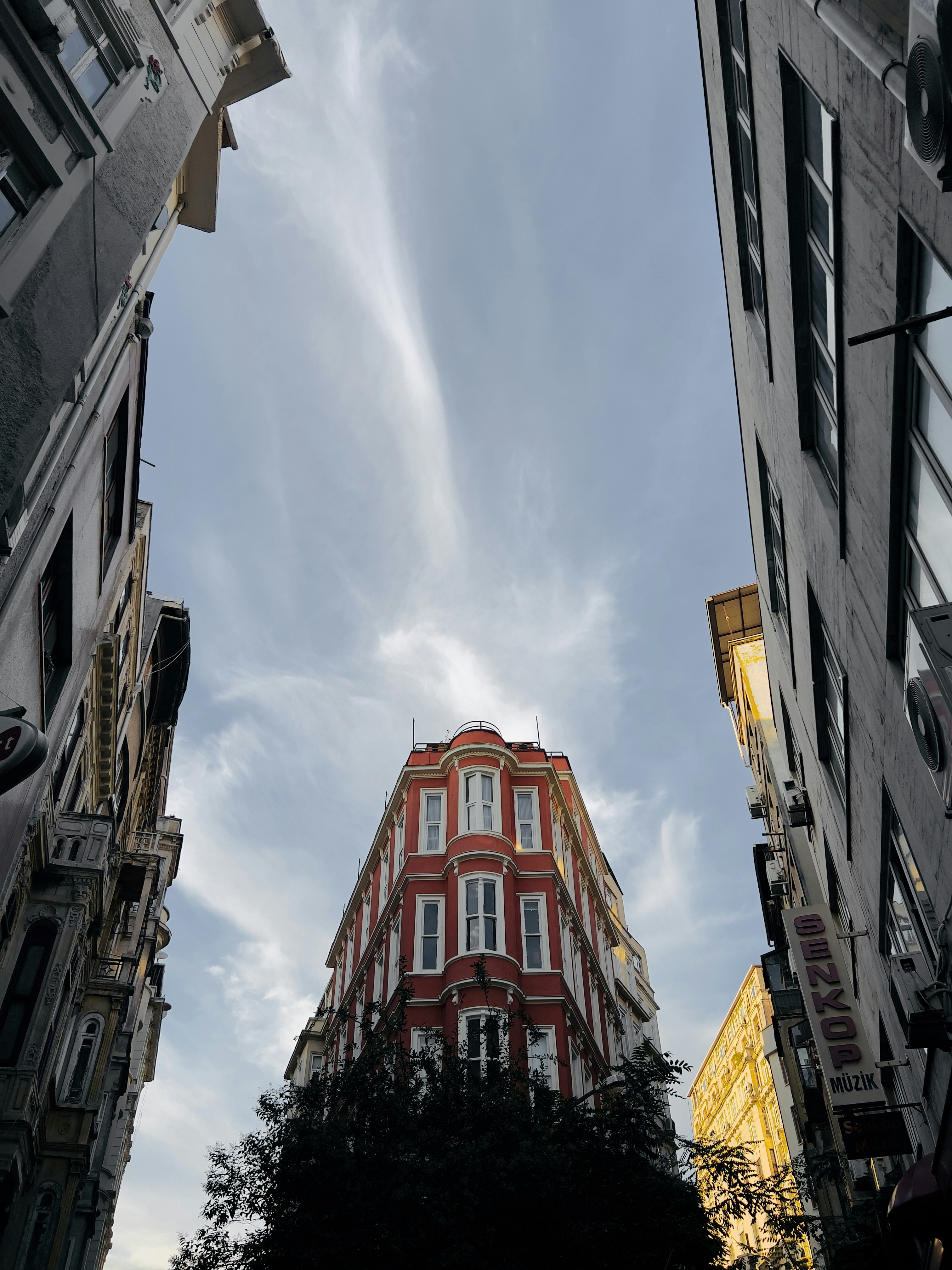 Red Victorian Tower Rising Between City Canyons
