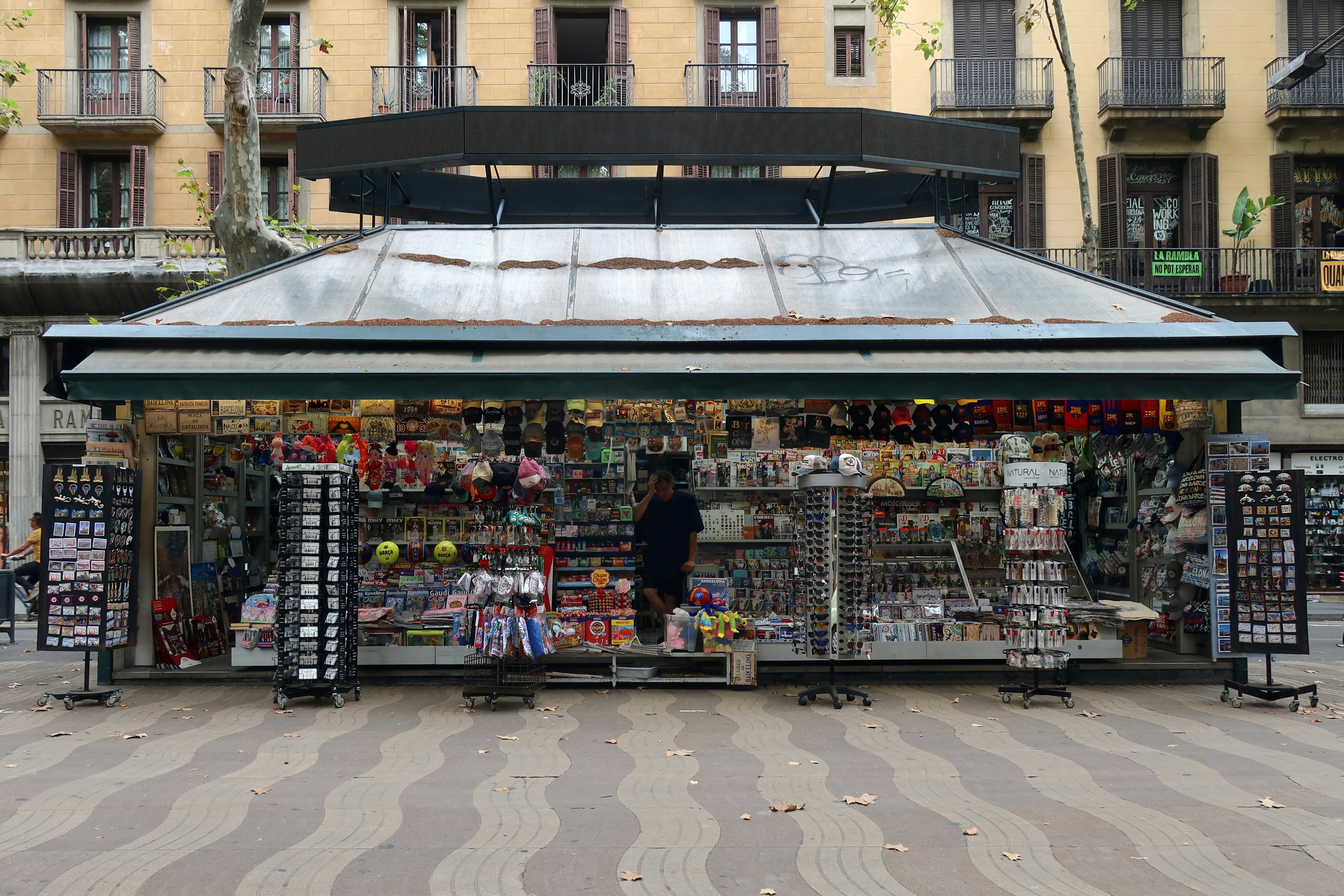 A news stand selling souvenirs on La Rambla in Barcelona | a person standing outside a shop