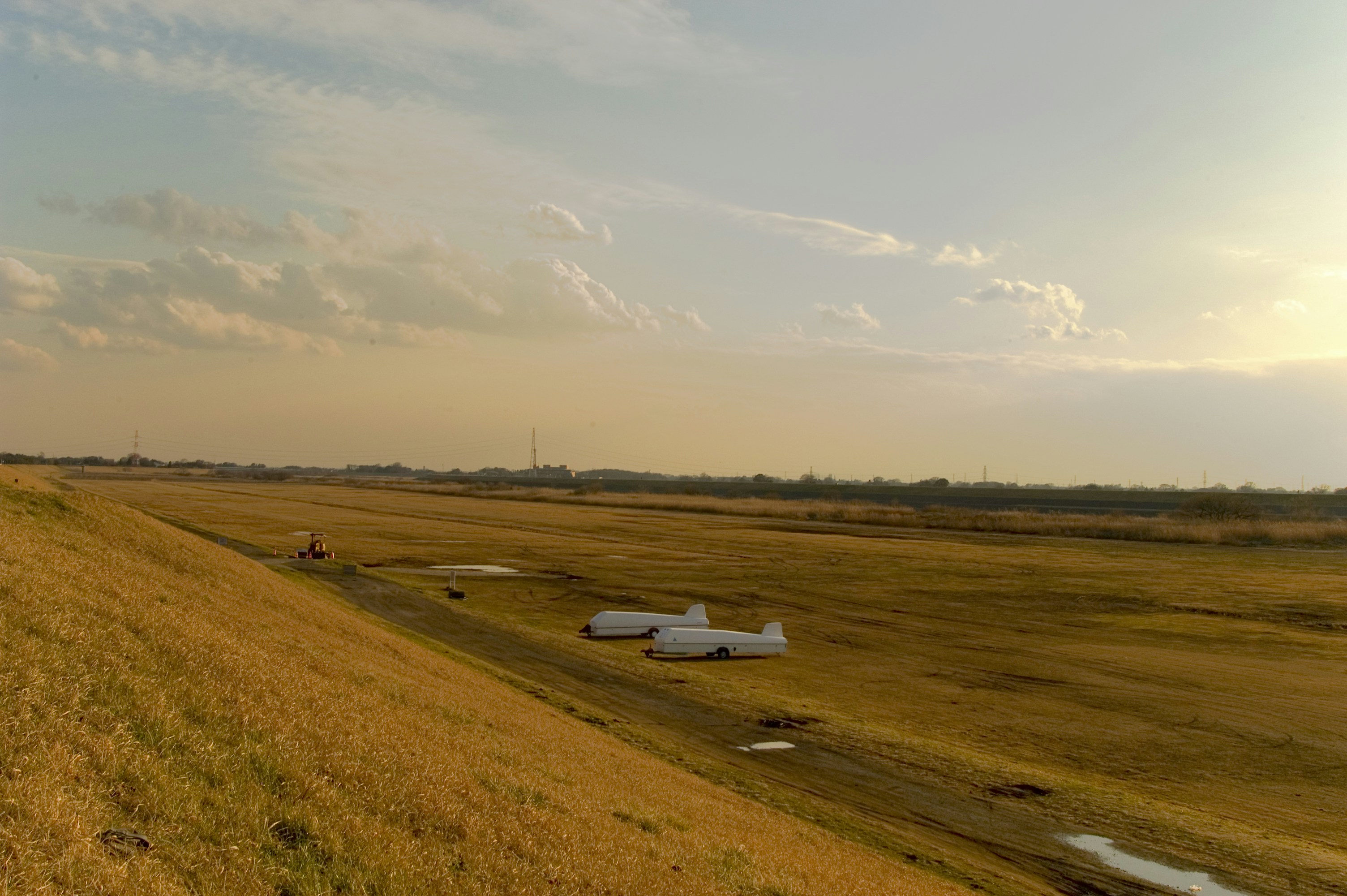 Abandoned aircraft resting on a sunlit field, surrounded by gentle hills and a vast sky. The scene evokes a sense of tranquility and nostalgia.