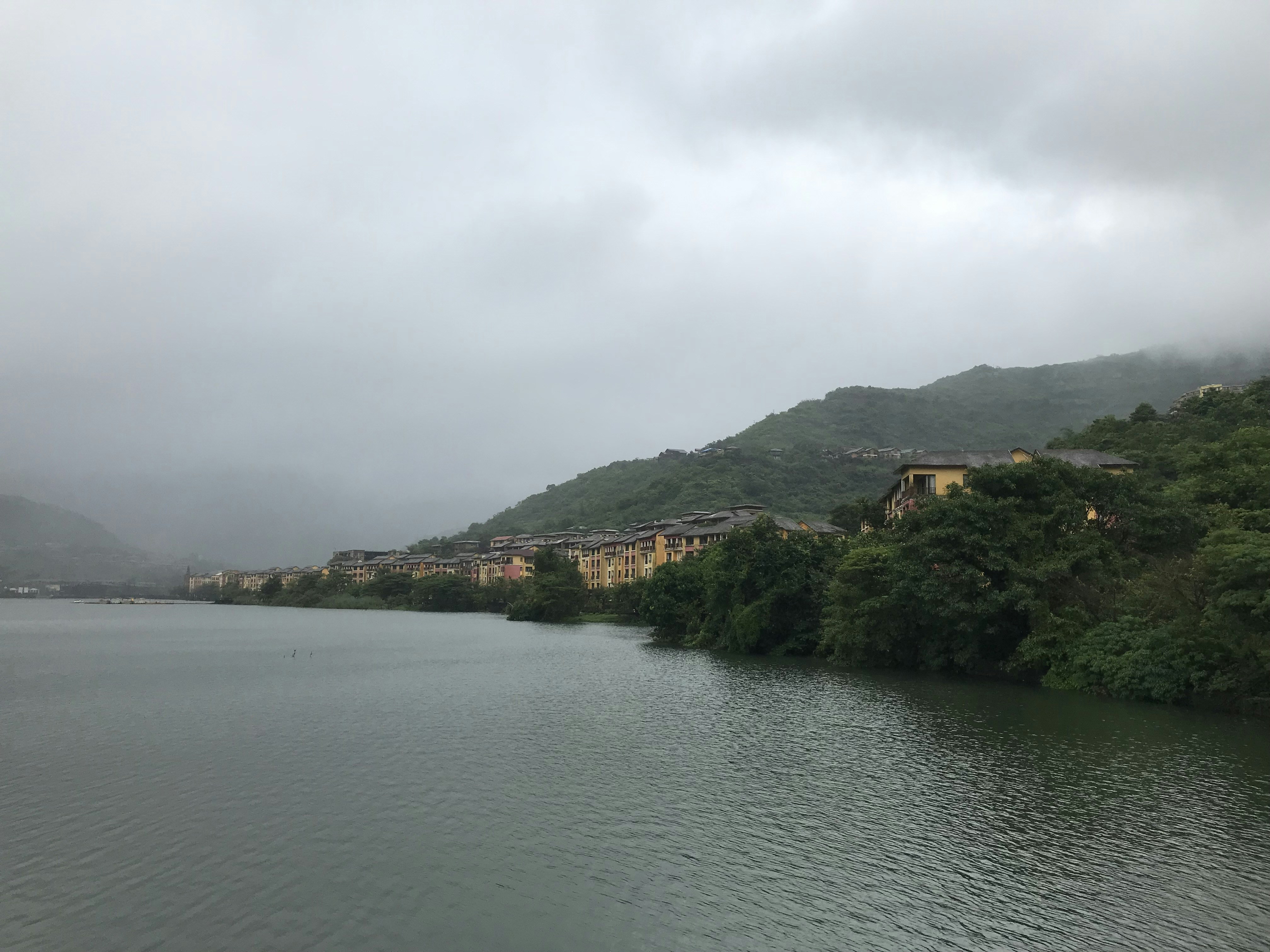 Misty Lakeside Village: Riverside Buildings Nestled Against Quiet Green Hills