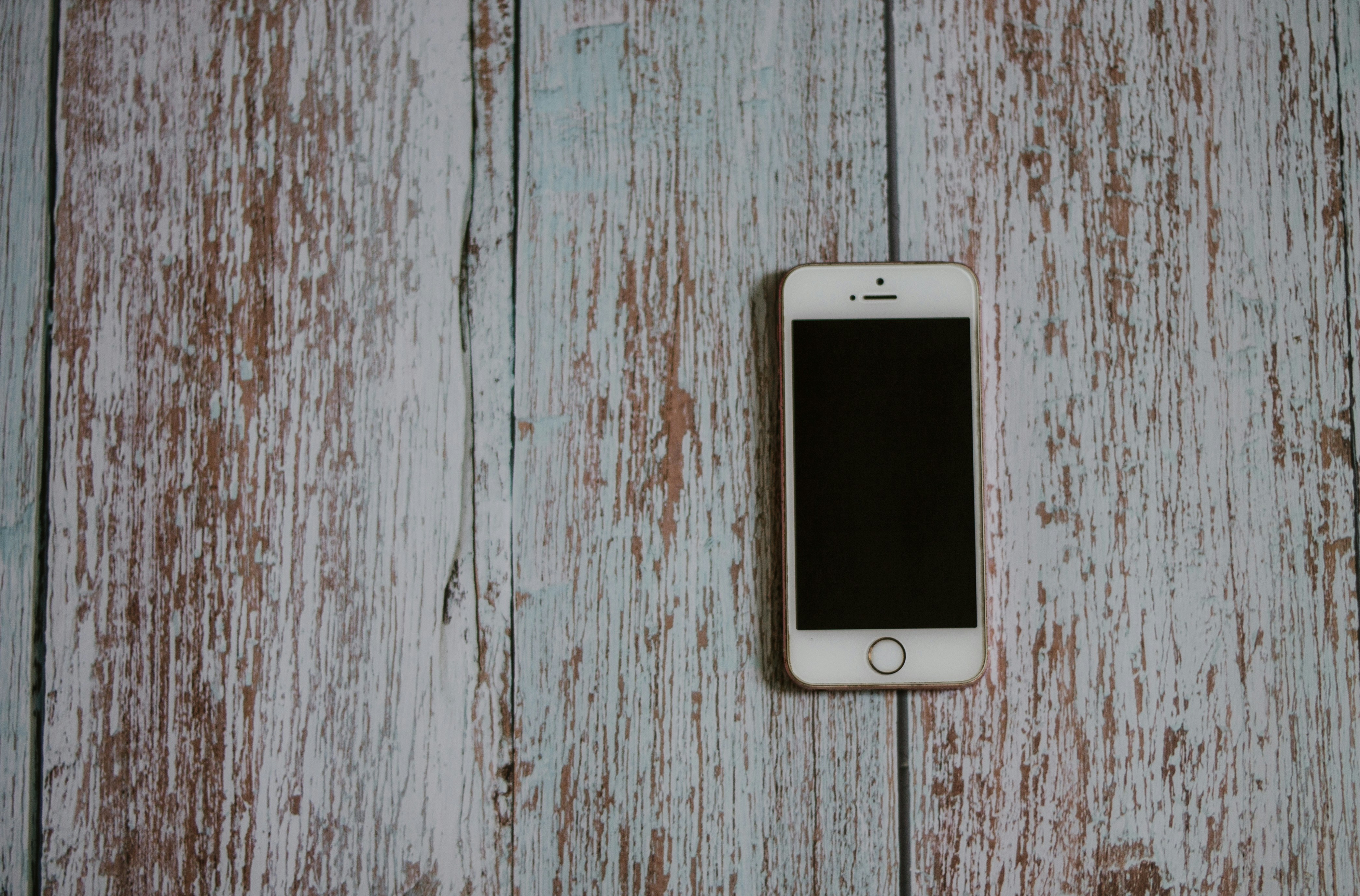 A white cell phone on a wooden surface photo – Free Iphone Image on ...