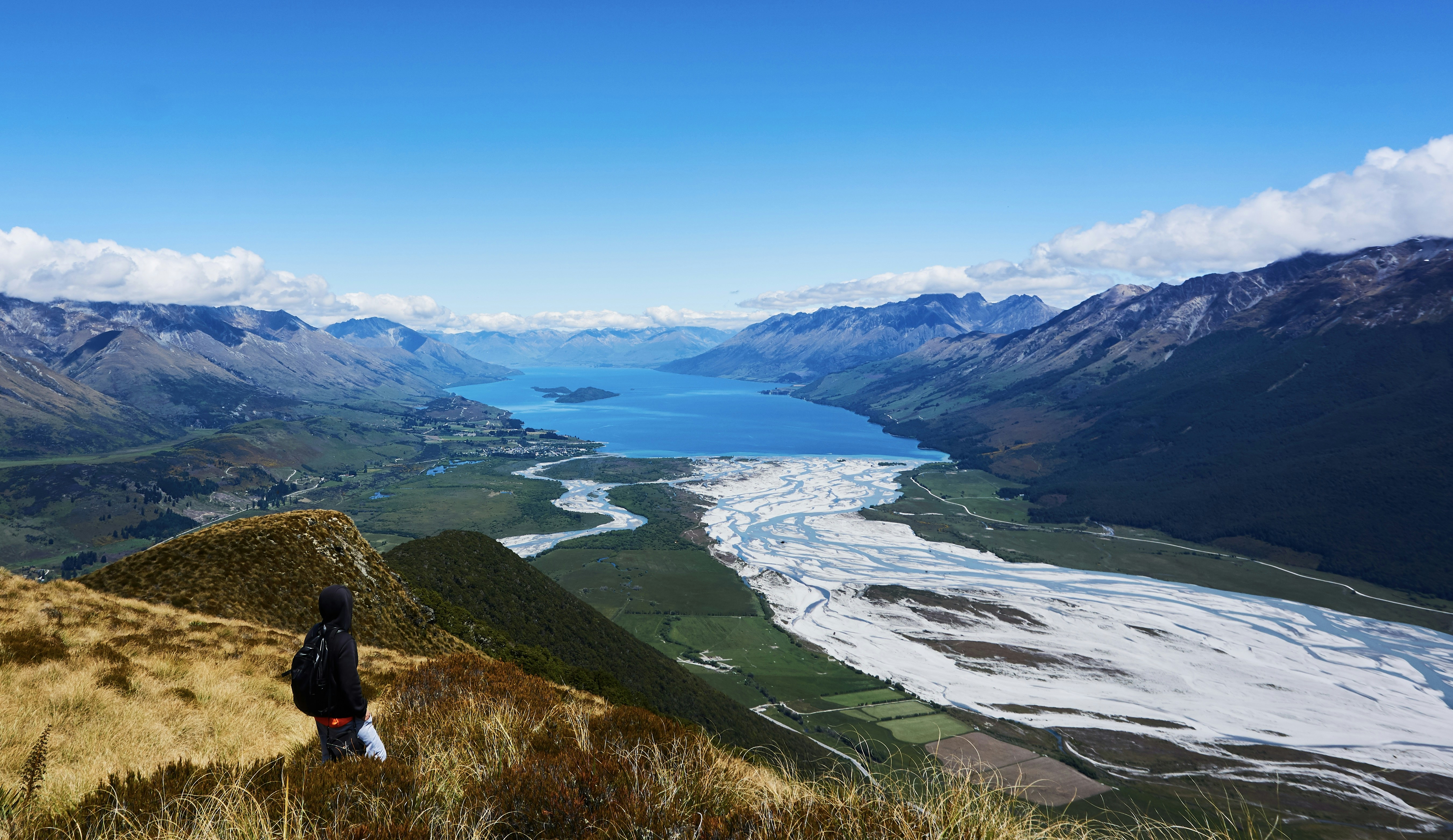 Hiker's Crest Over Valley: Serpentine River Framing an Azure Lake