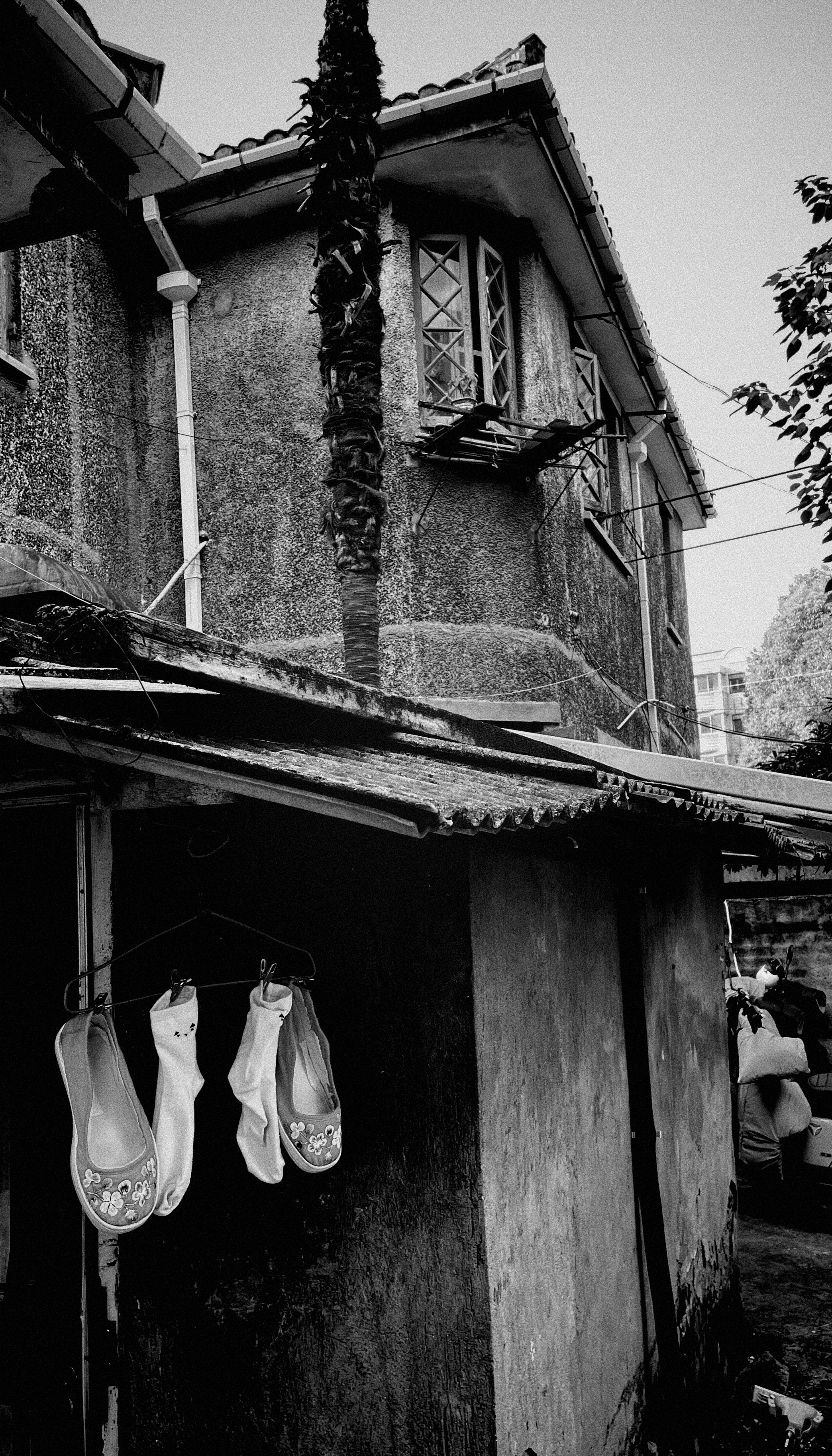 Weathered Roofline and Shoes: A Quiet Courtyard Portrait