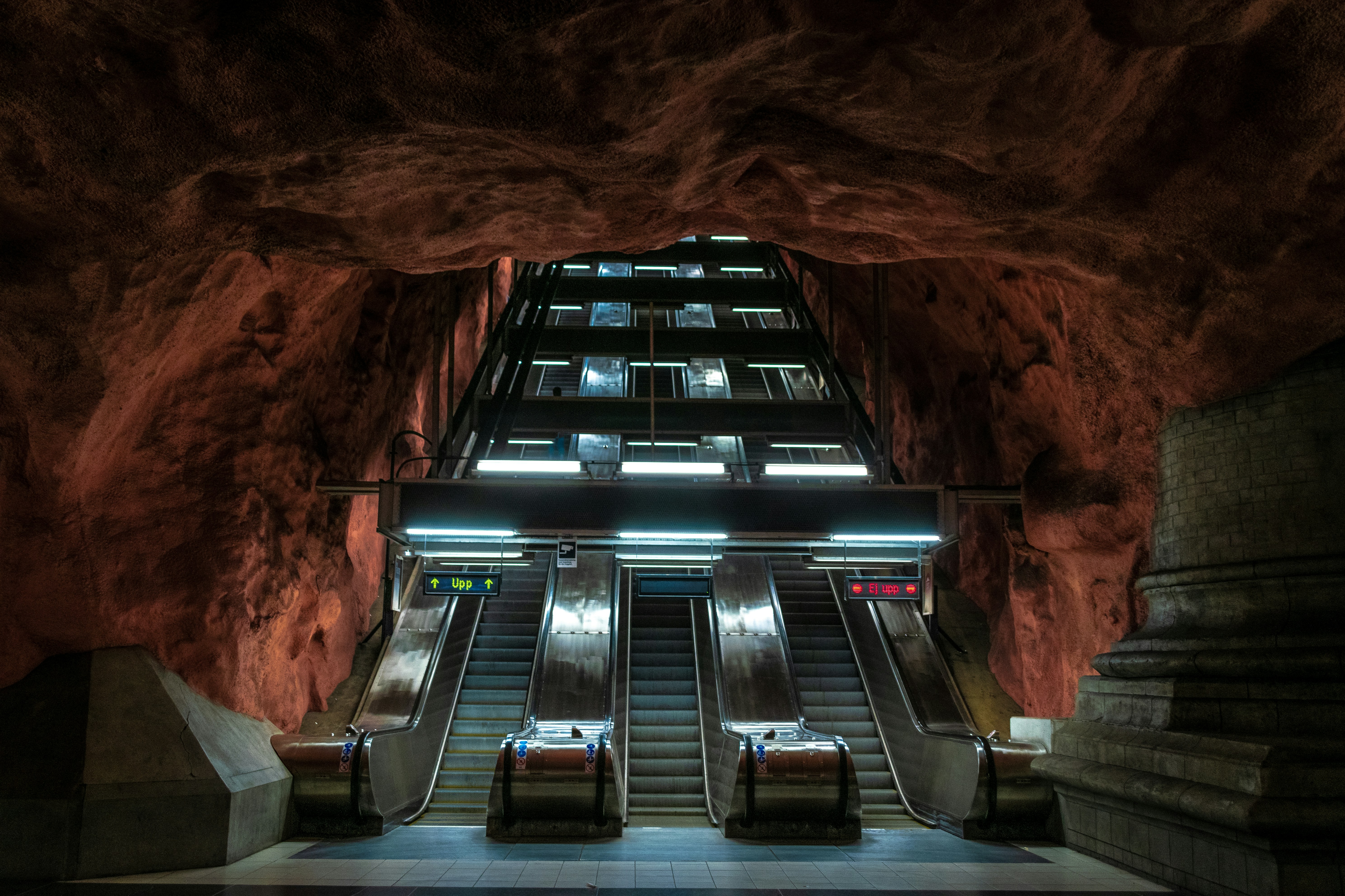 Underground Ascent: Escalators Behind a Red Rock Spine