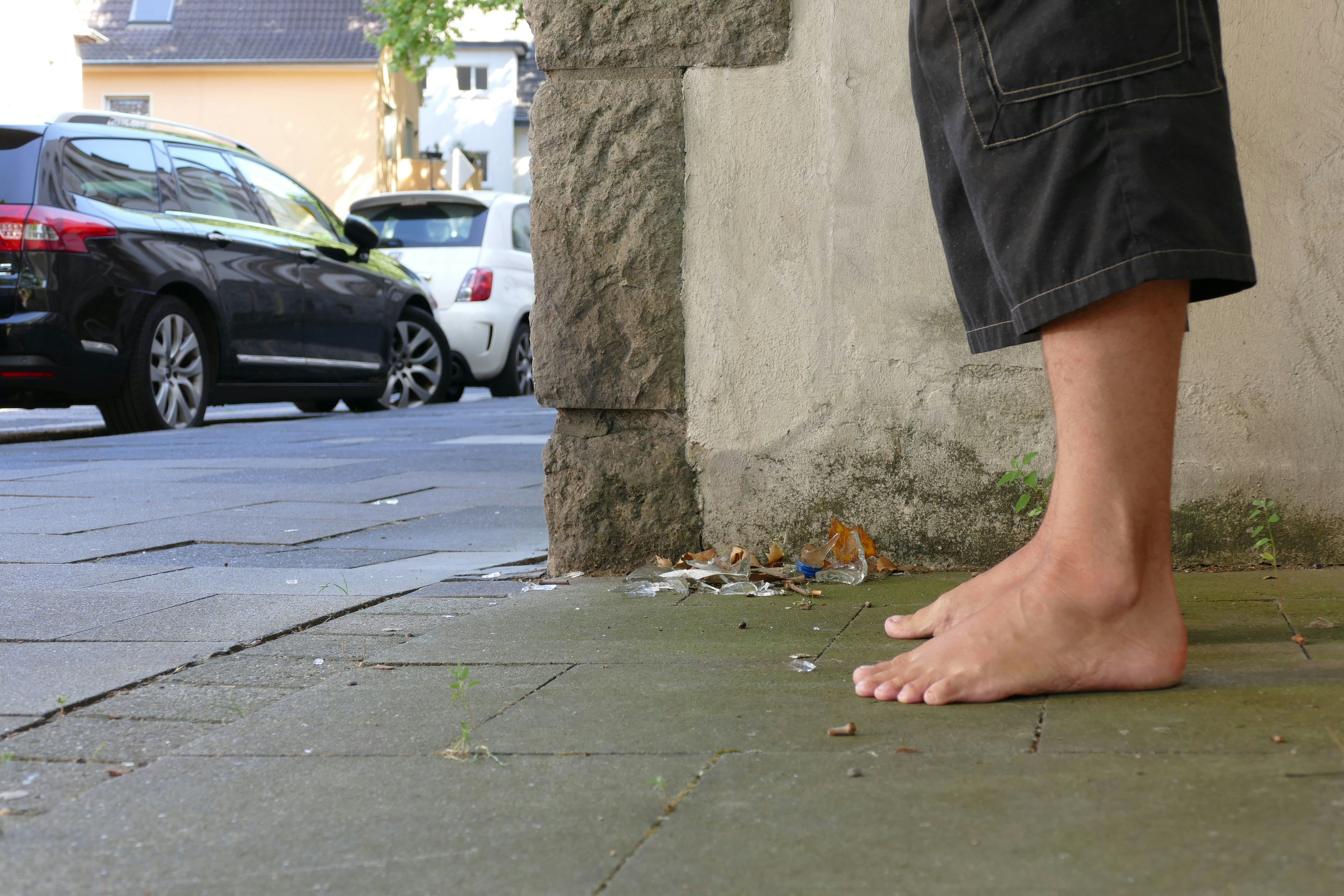 Barefoot in the city over garbage and broken glass.