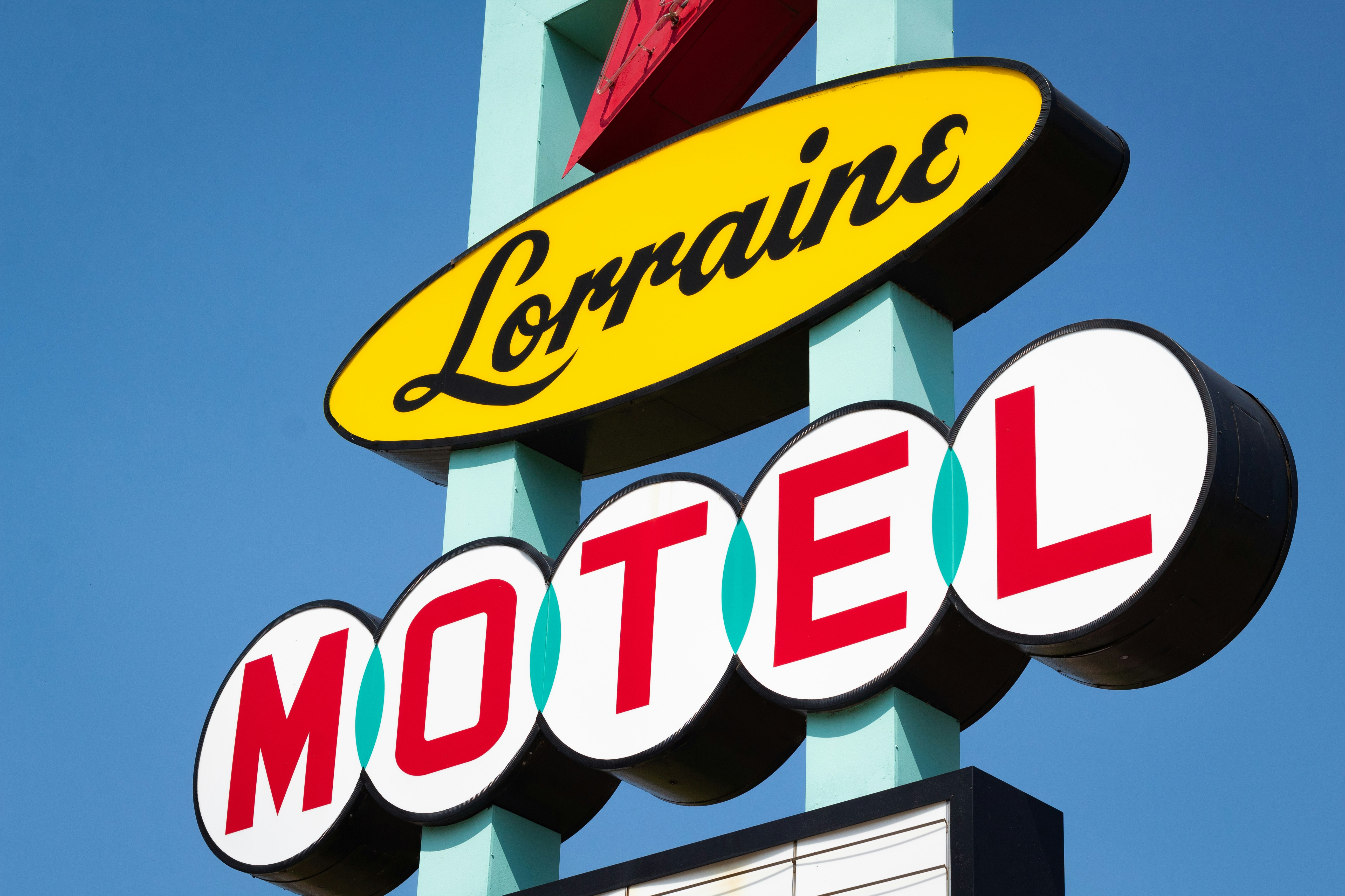 Vibrant vintage sign for the Lorraine Motel featuring bold colors and retro typography against a clear blue sky.