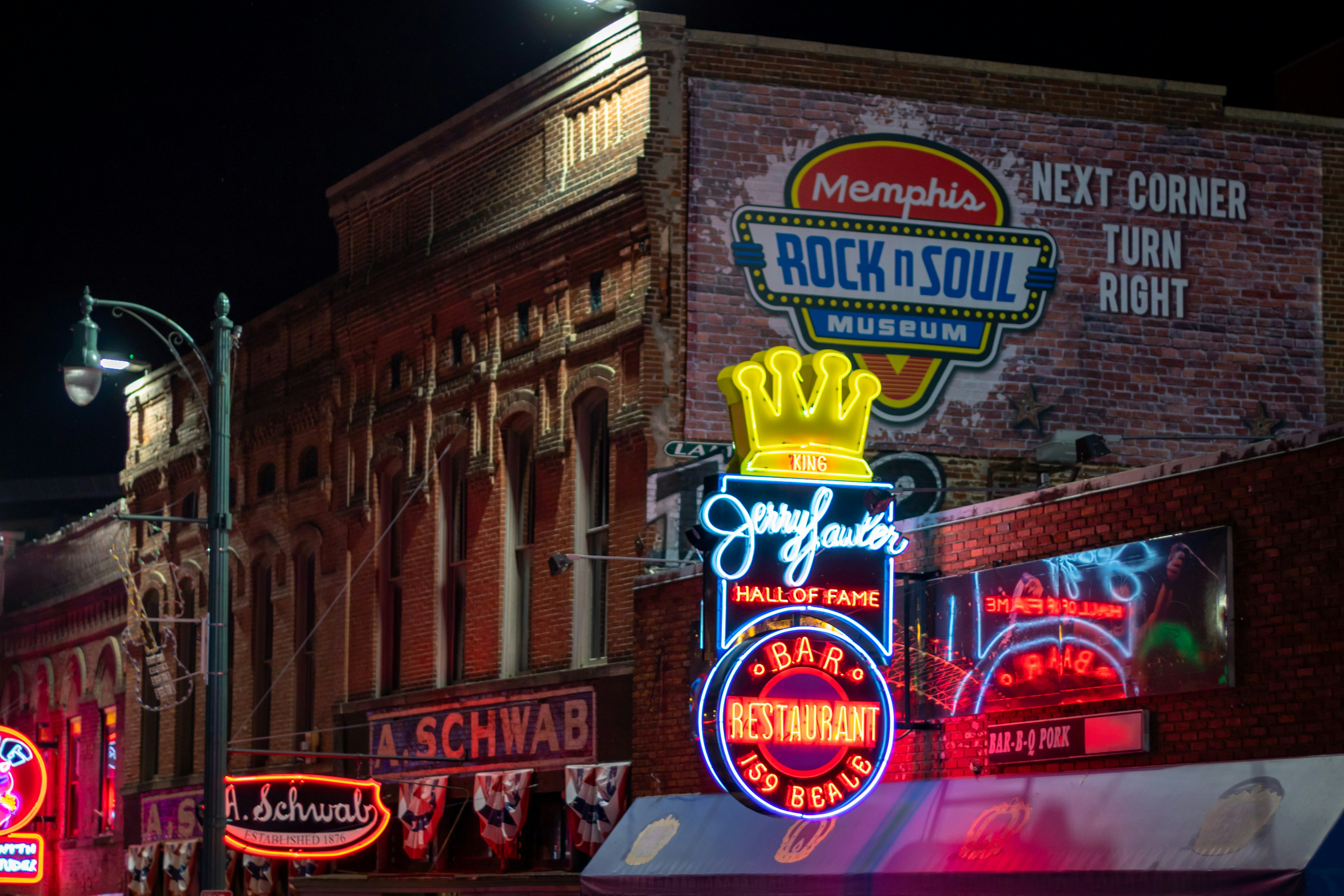 Illuminated neon signs adorn the historic buildings of Beale Street, showcasing the rich musical heritage of Memphis. The Rock 'n' Soul Museum is prominently featured, inviting visitors to explore its legacy.