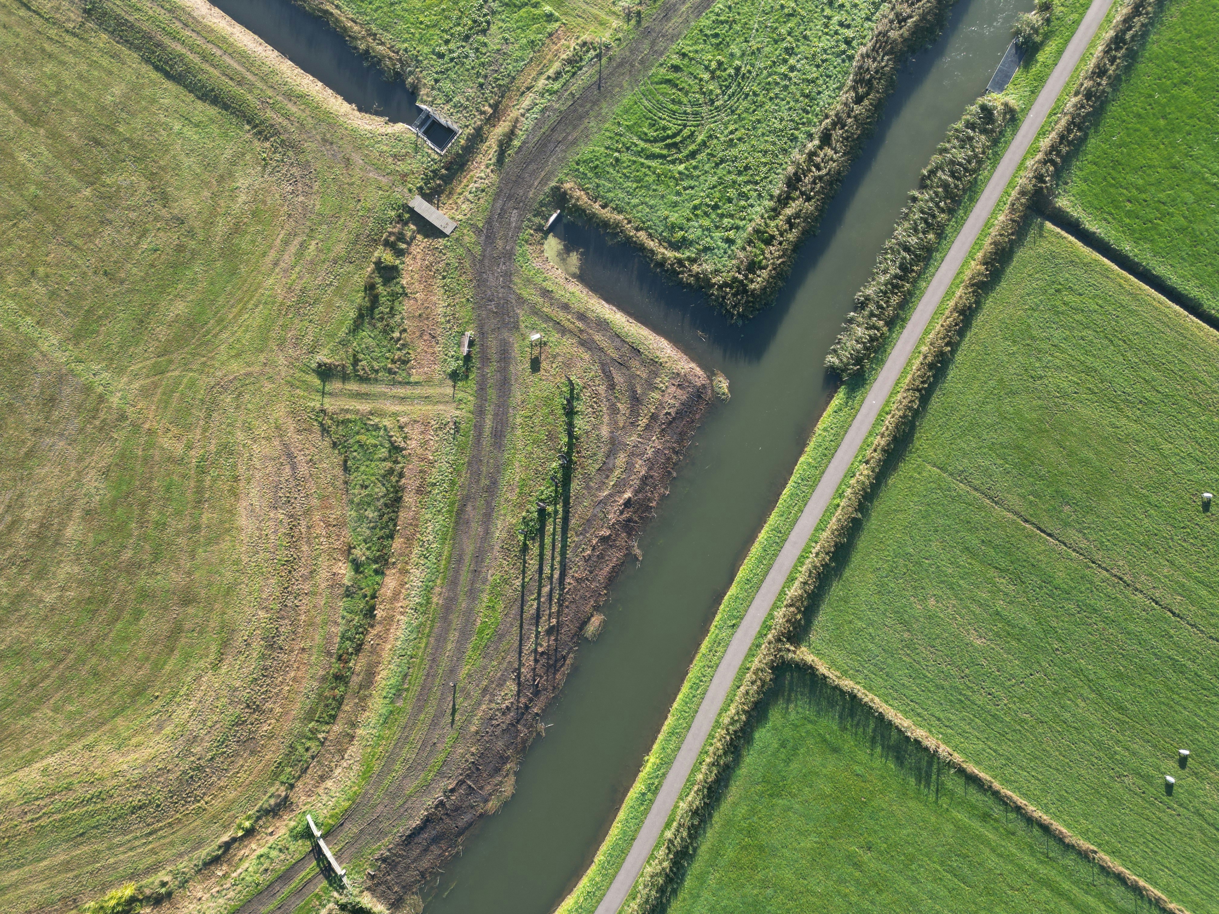 Aerial view of intersecting roads and canals amidst lush green fields.