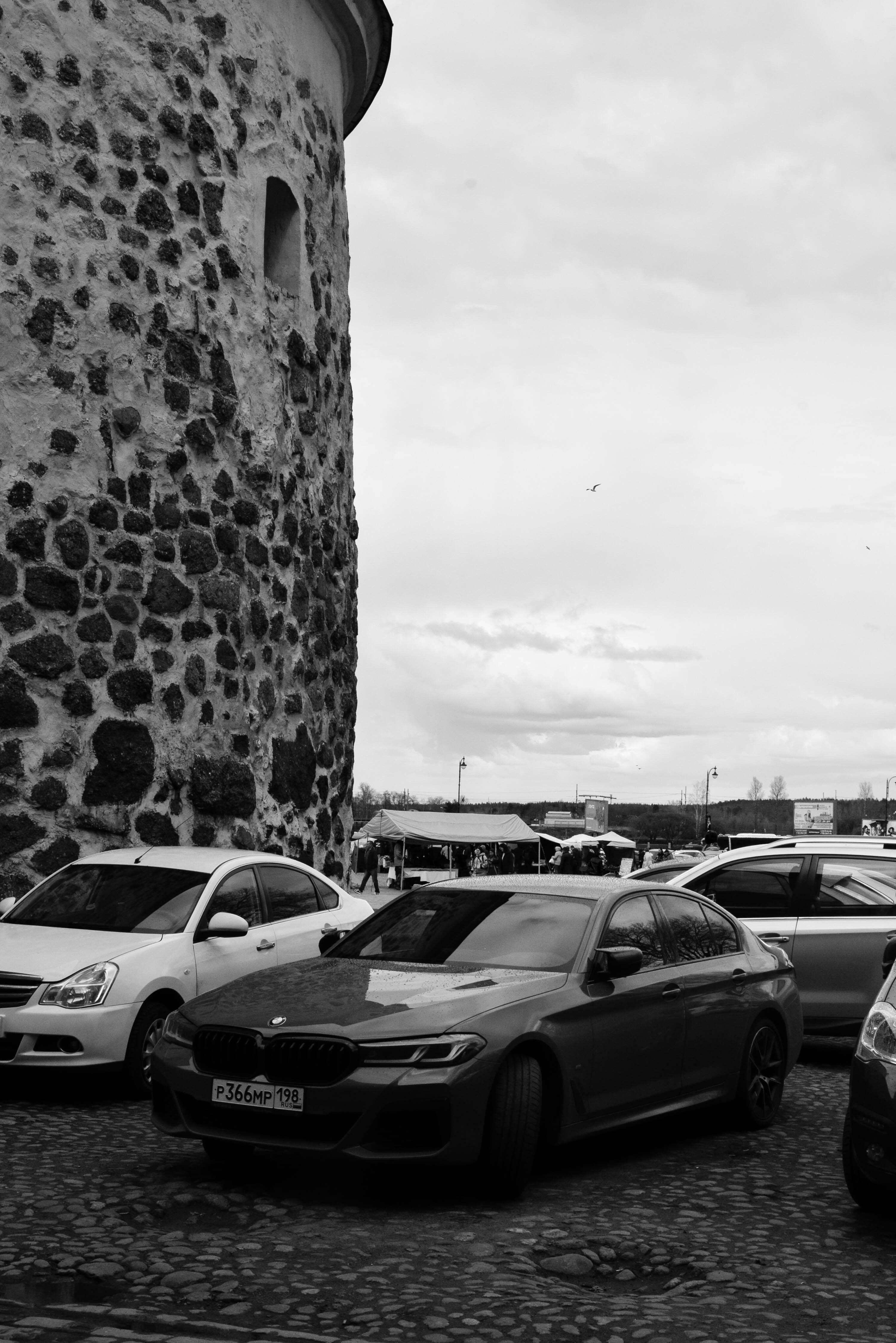 Cobblestone Sentinel: Cars at the Foot of the Fortress