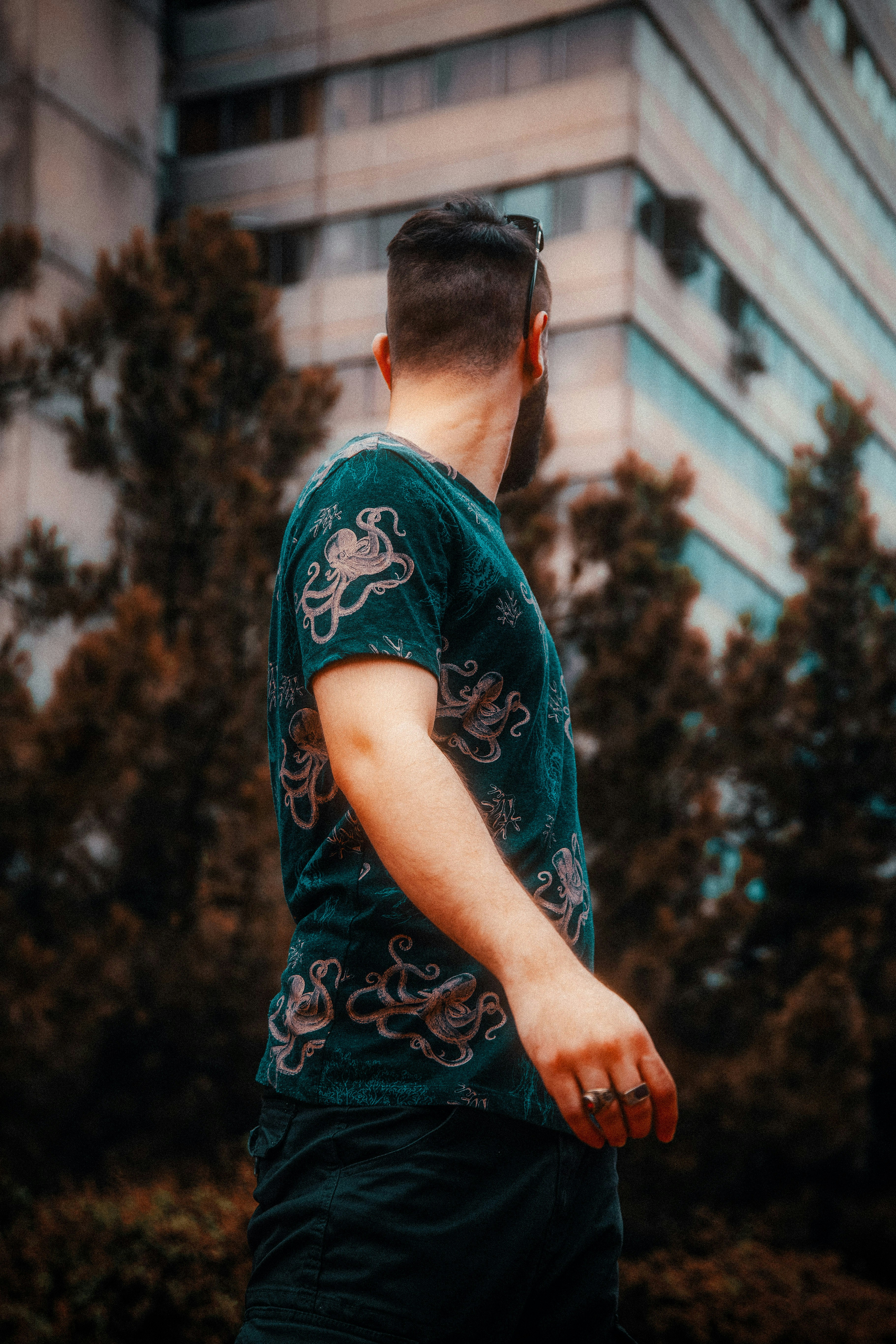 Urban Portrait: A Man in Patterned Teal Steps Away from the Glassy Facade