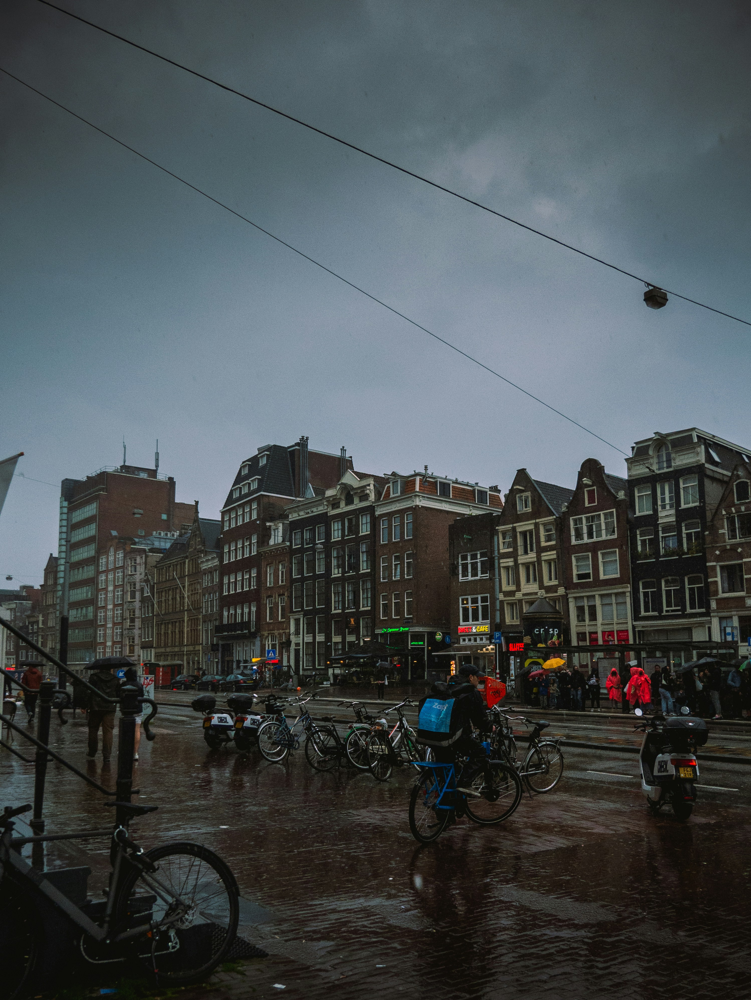 Rainy Amsterdam: a bicycle-filled street framed by brick gables and moody skies