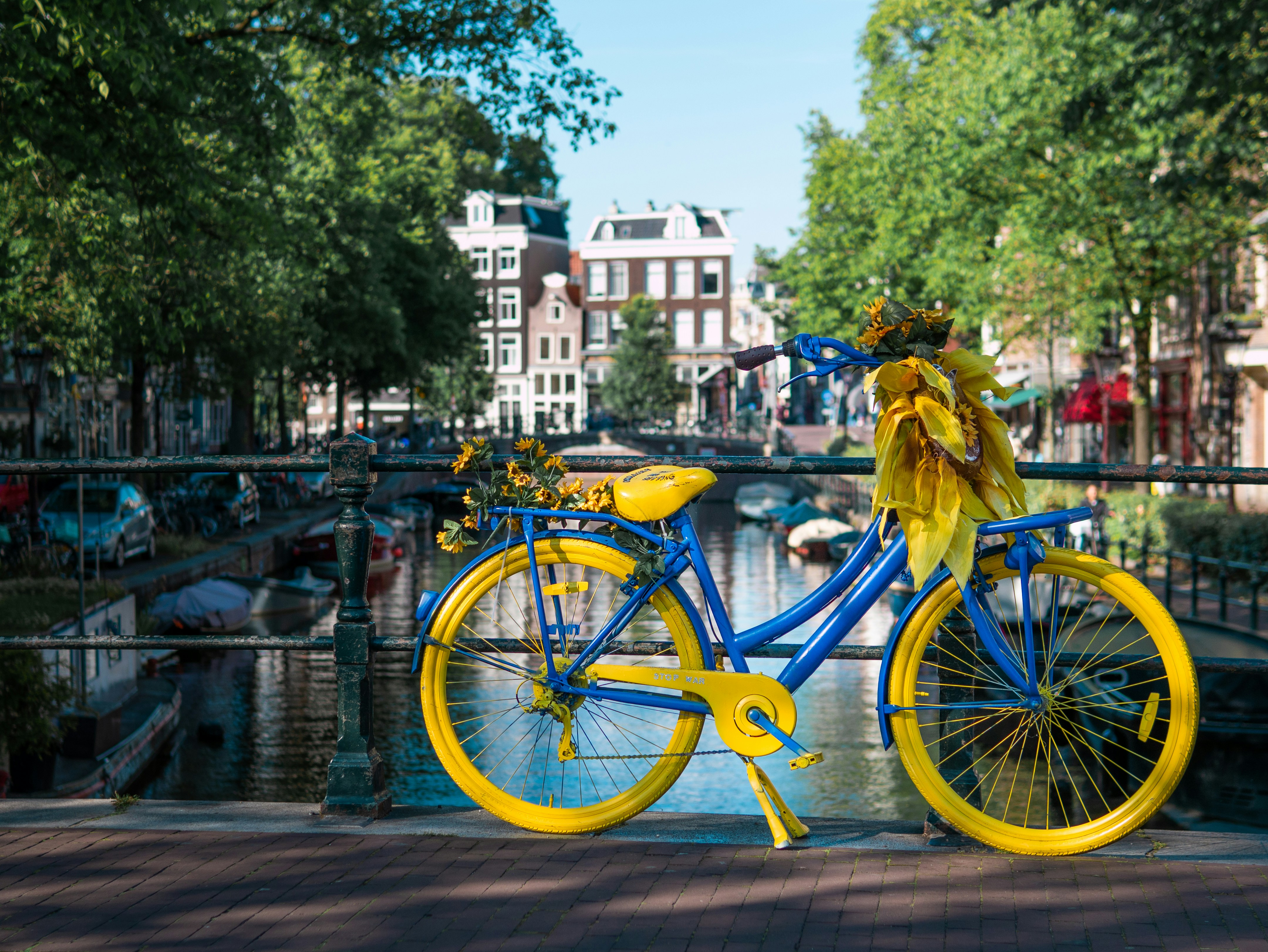 Bright Yellow Bicycle Anchored on a Blue-Frame Canal Bridge