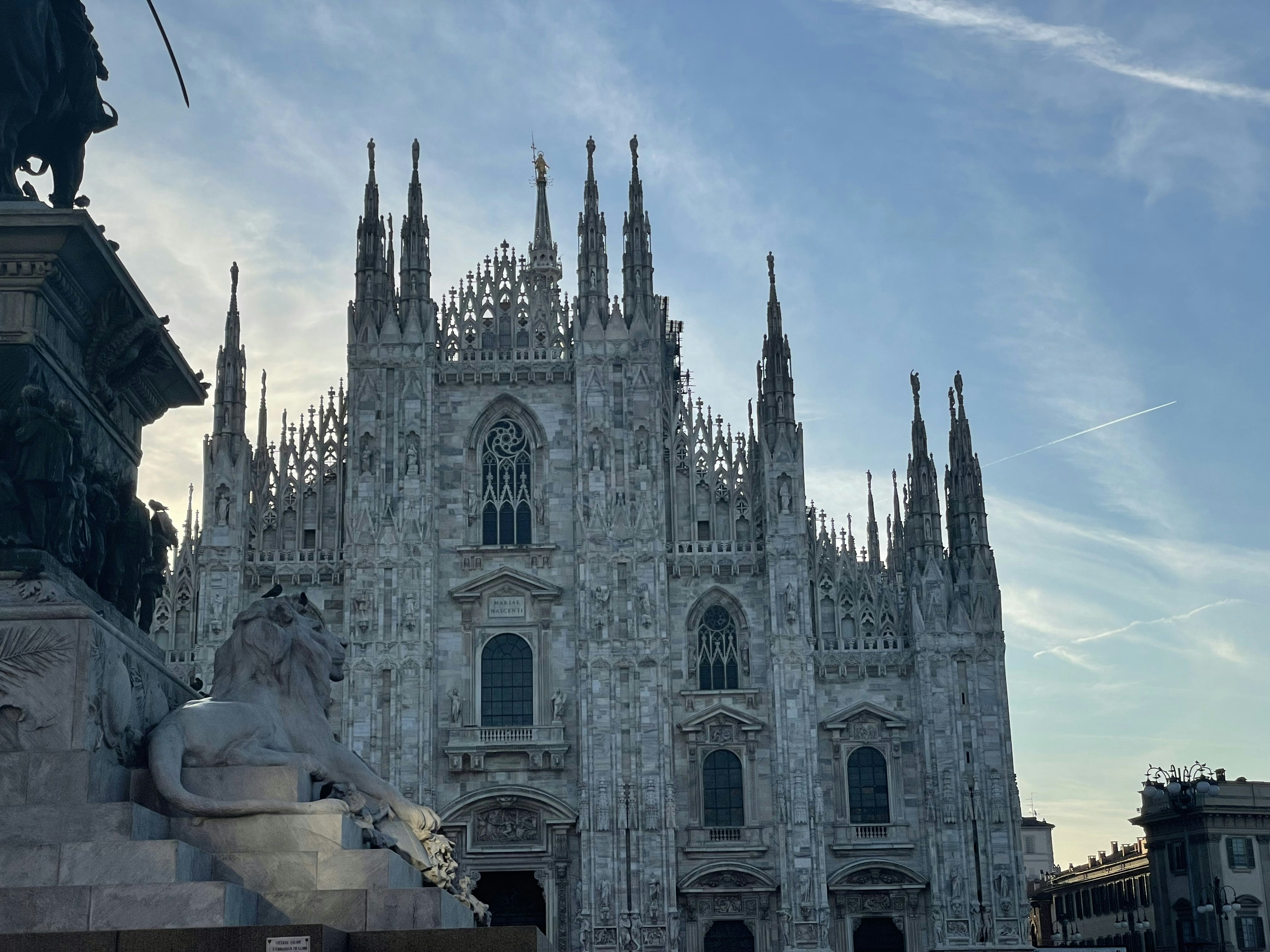 Intricate Gothic architecture of the Duomo di Milano, showcasing its ornate spires and detailed sculptures in the early evening light.