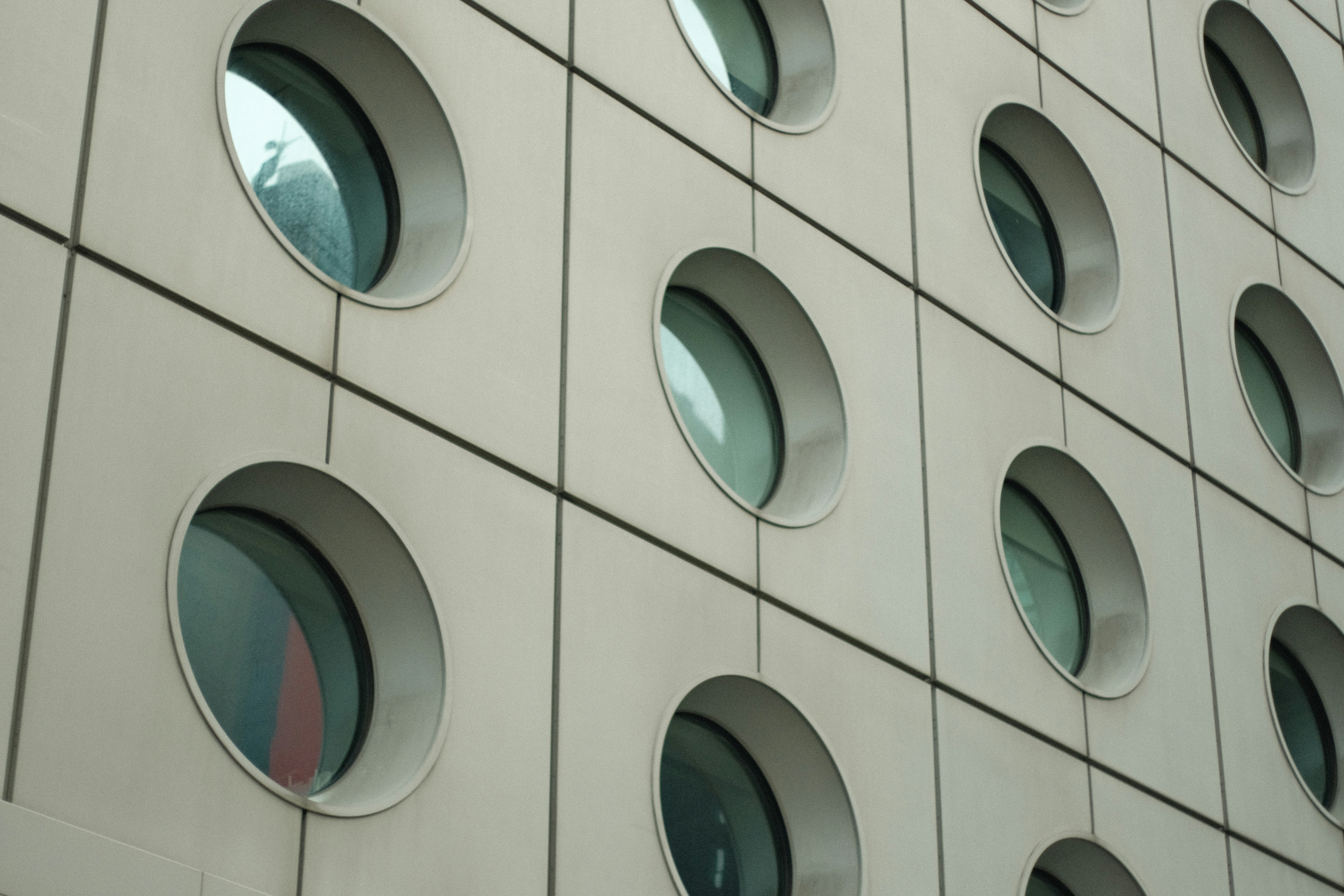 Architectural close-up of a building's facade featuring a series of circular windows, creating a rhythmic visual pattern.
