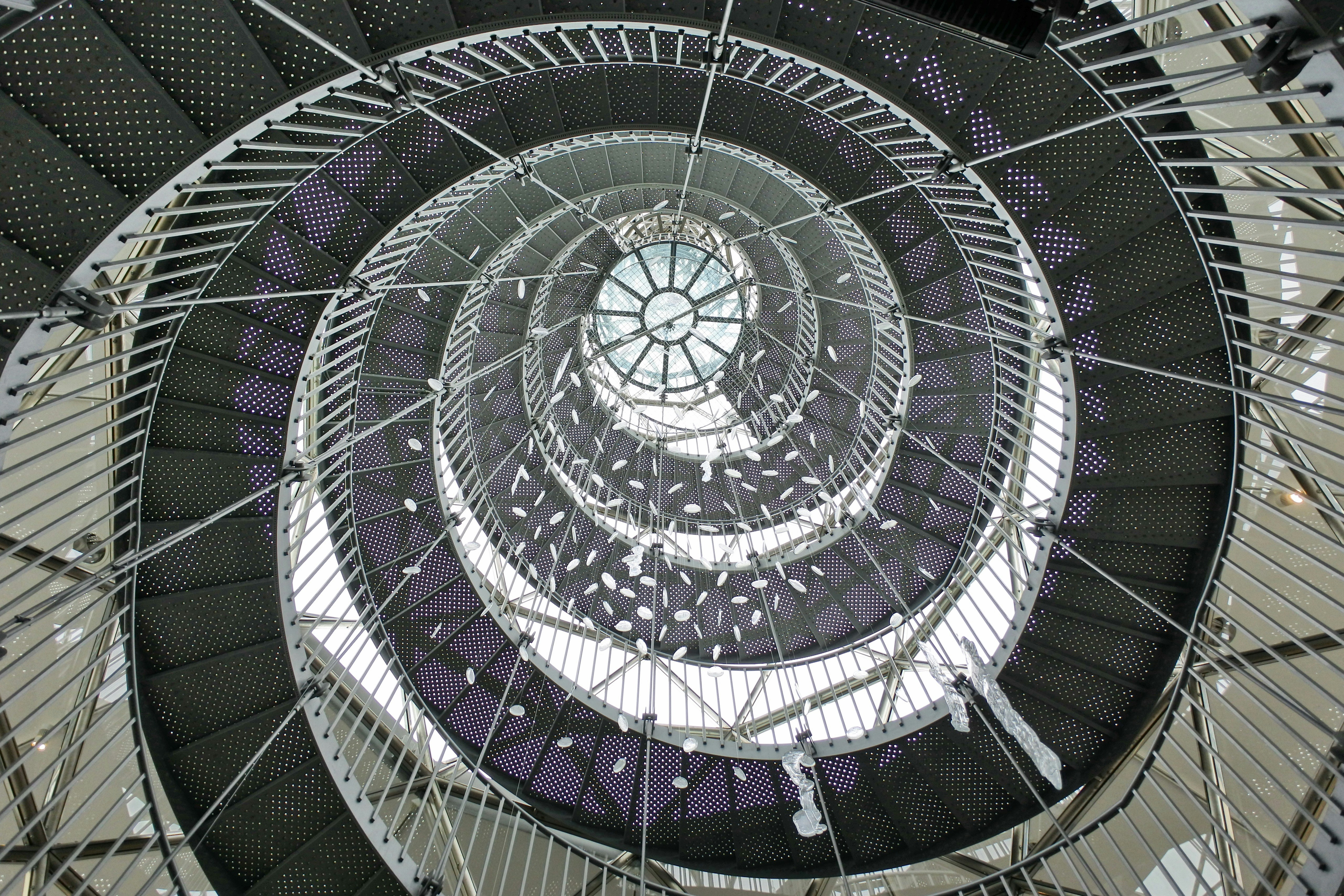 Intricate spiral staircase viewed from below, showcasing a circular geometric pattern.