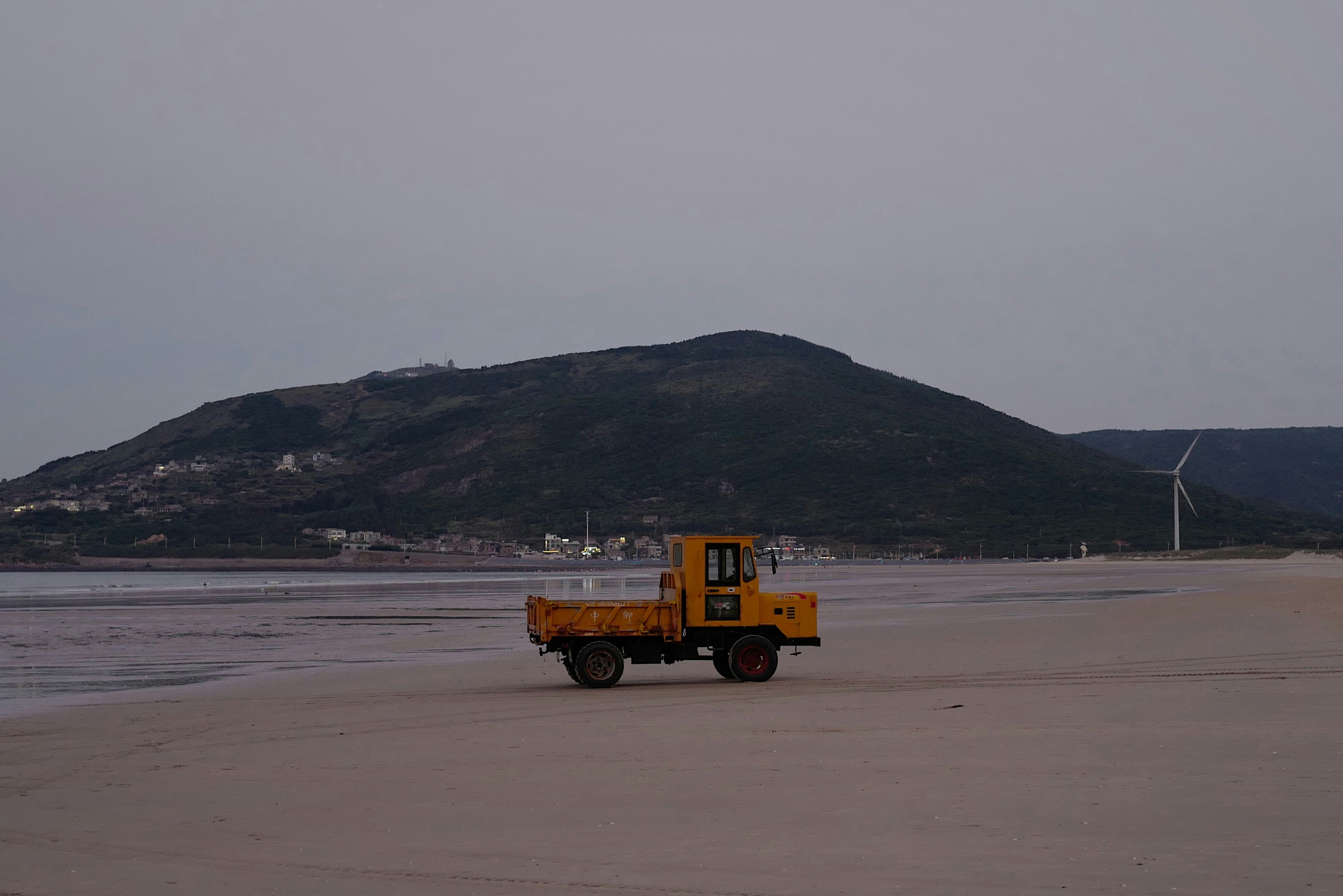 Lone Yellow Truck on a Wind-Swept Beach at Dusk