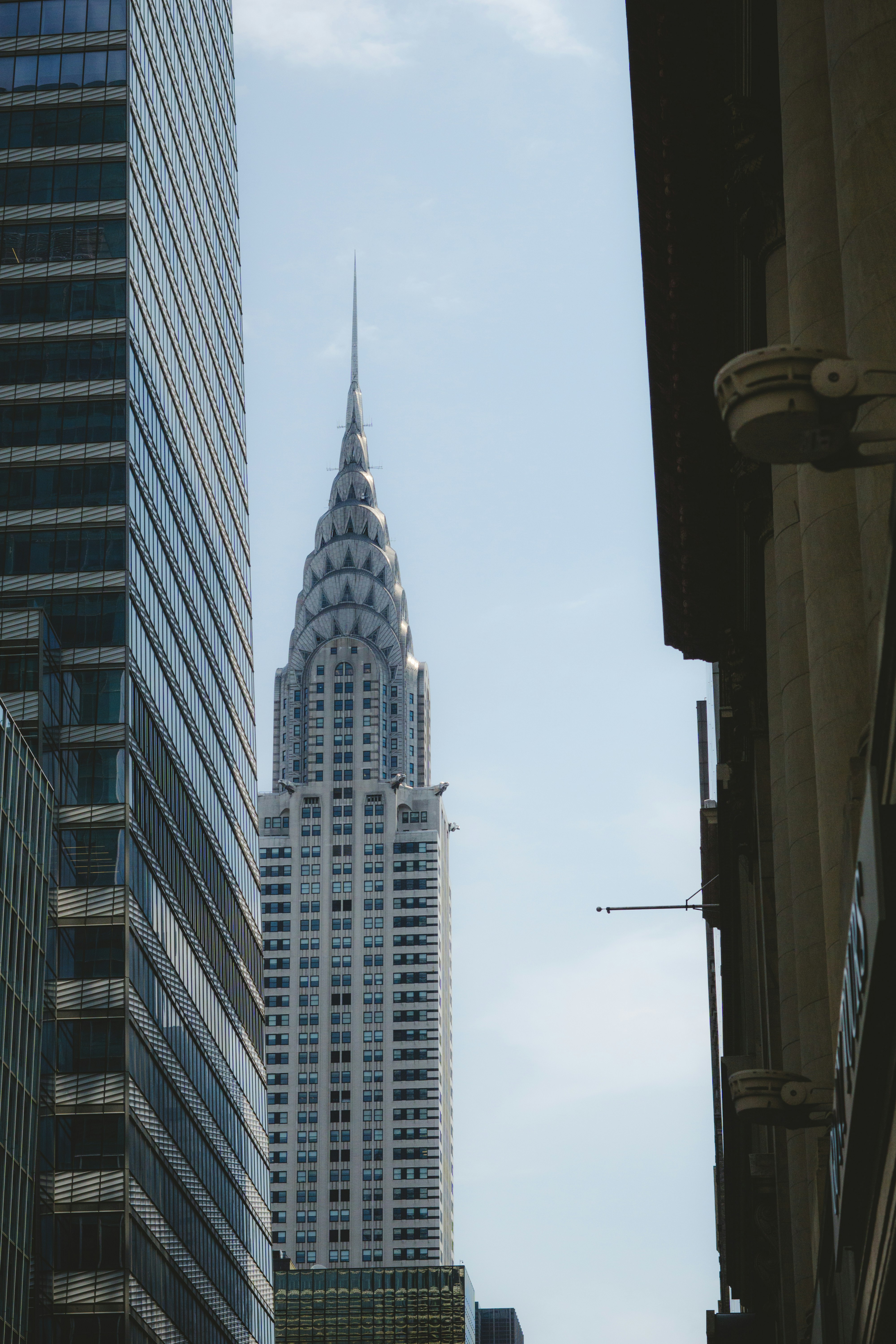 A tall building with a pointy top with chrysler building in the ...