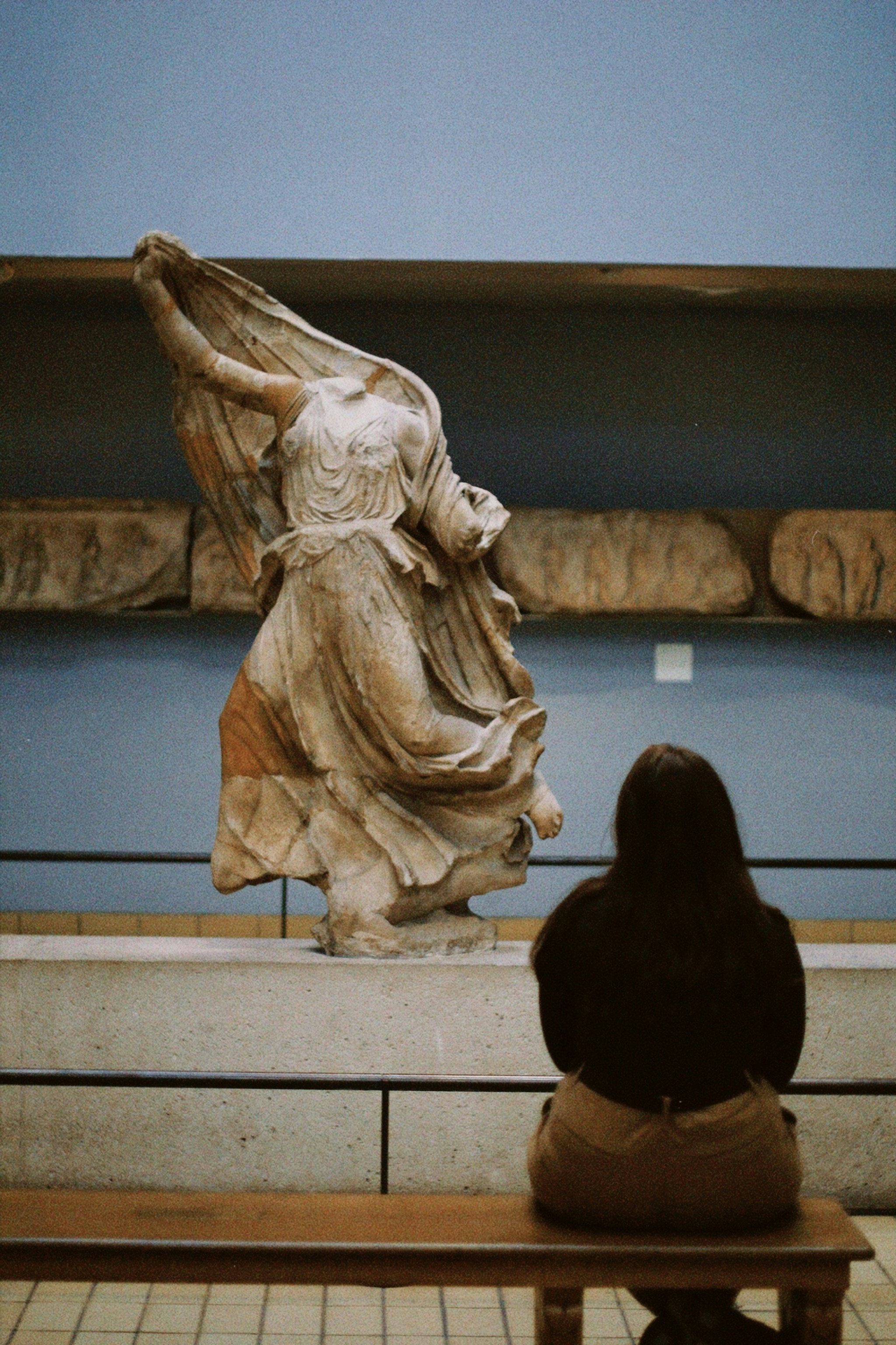 a person sitting on a bench looking at a statue
