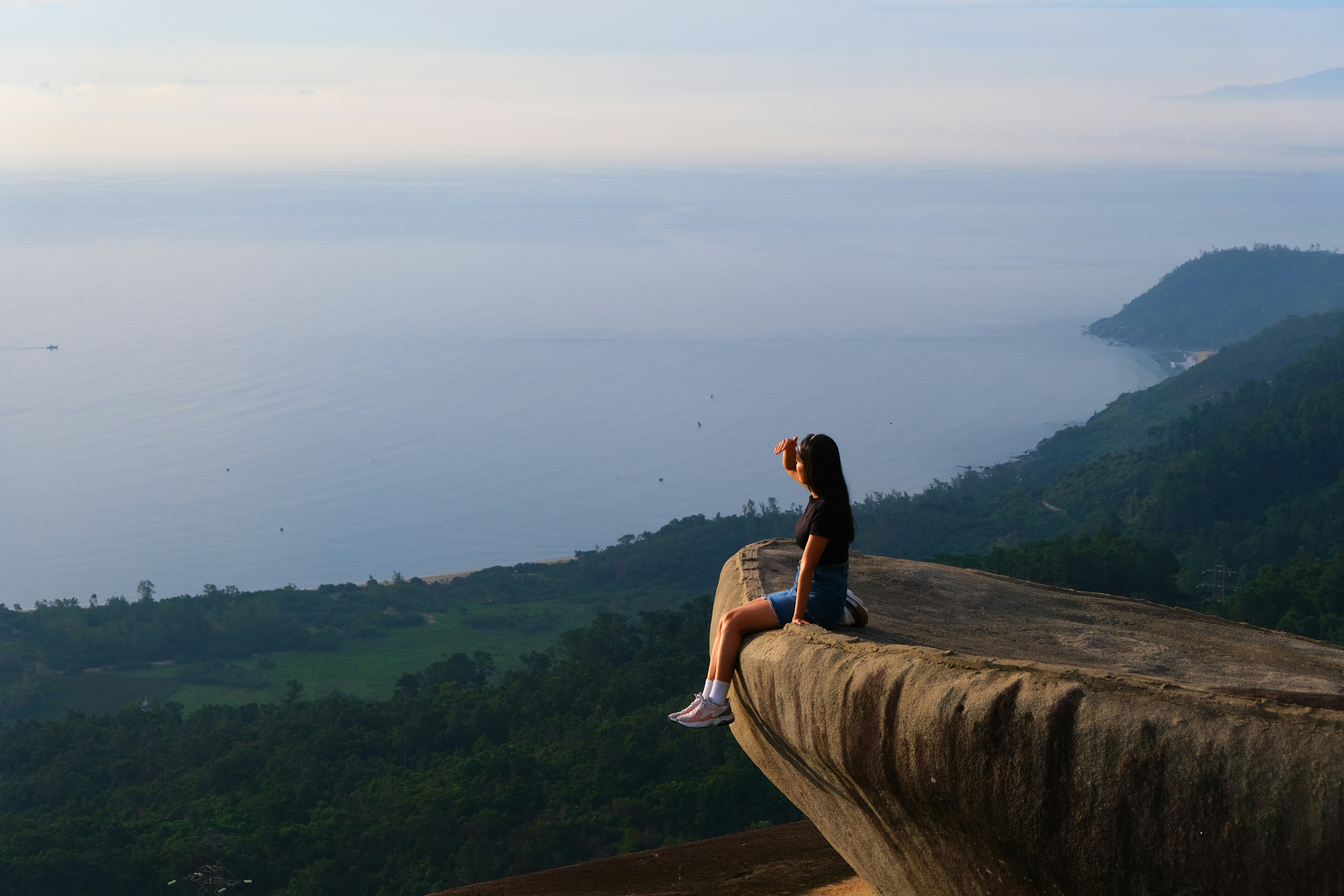 A man sitting on a ledge overlooking a valley photo – Free Person Image ...