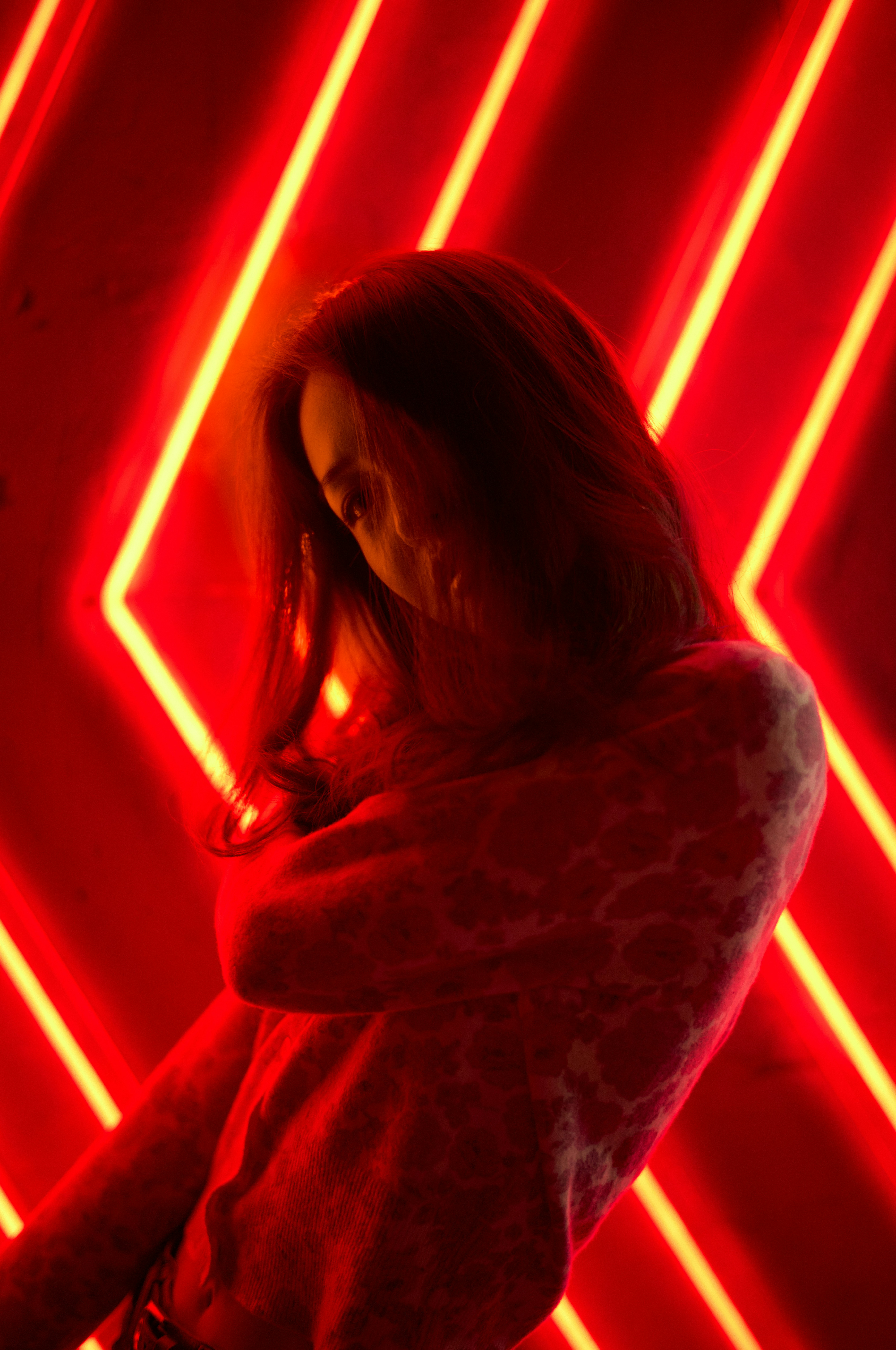 Portrait of a woman bathed in crimson neon light, her face softly lit by diagonal red lines.