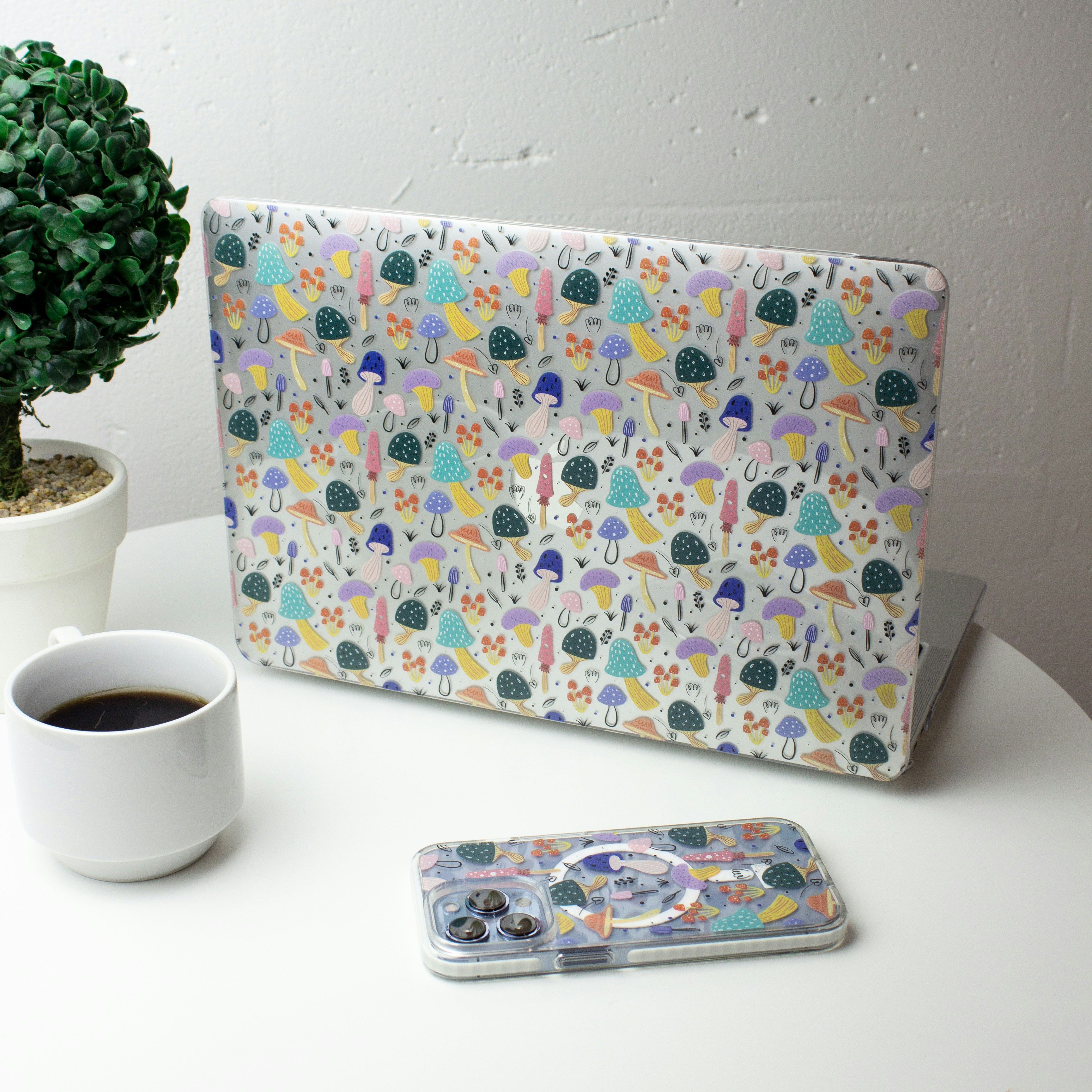 Patterned laptop sleeve and matching phone case on a clean desktop